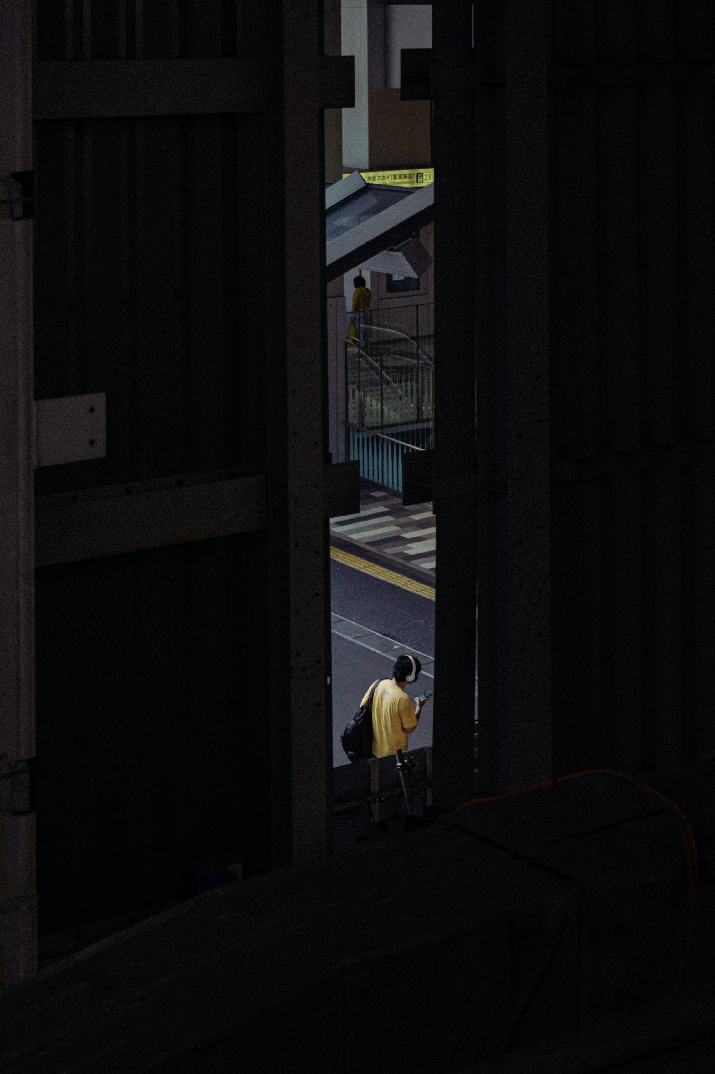 Yellow-Jacketed Figure Through a Subway Gap