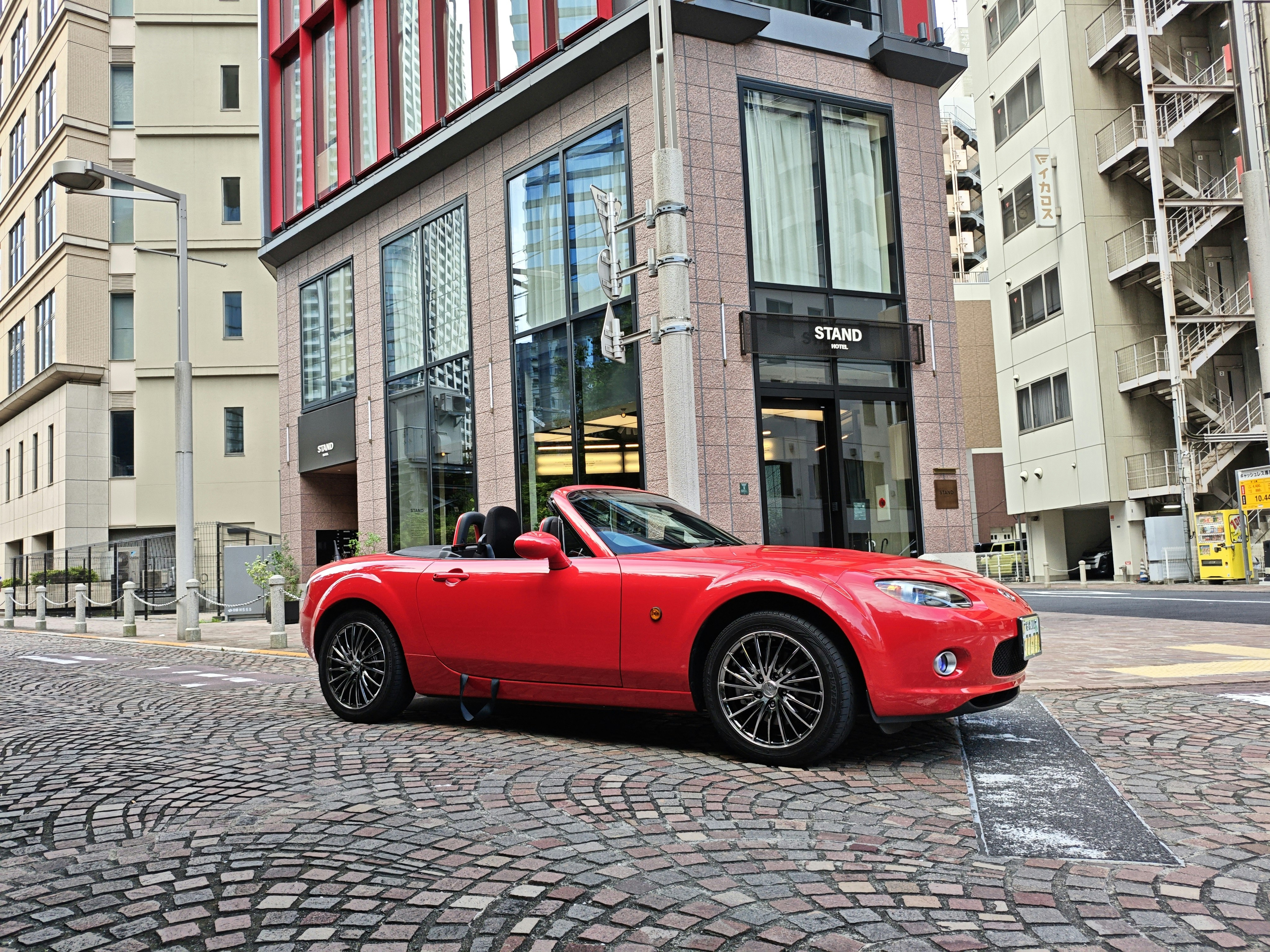 A red convertible sports car parked on a city street.