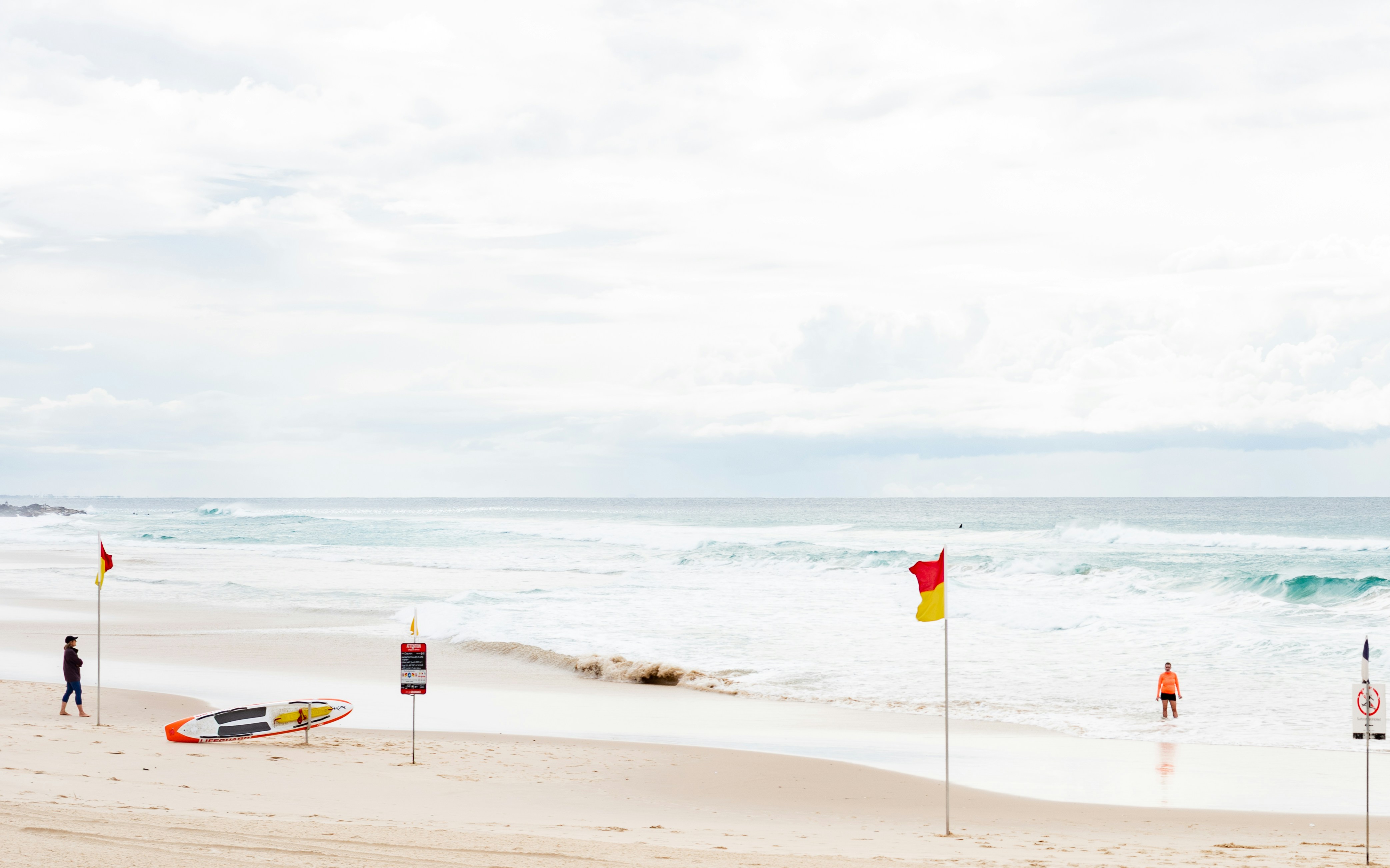 Surfboard on the Quiet Shore: Flags and Waves in the Morning Light