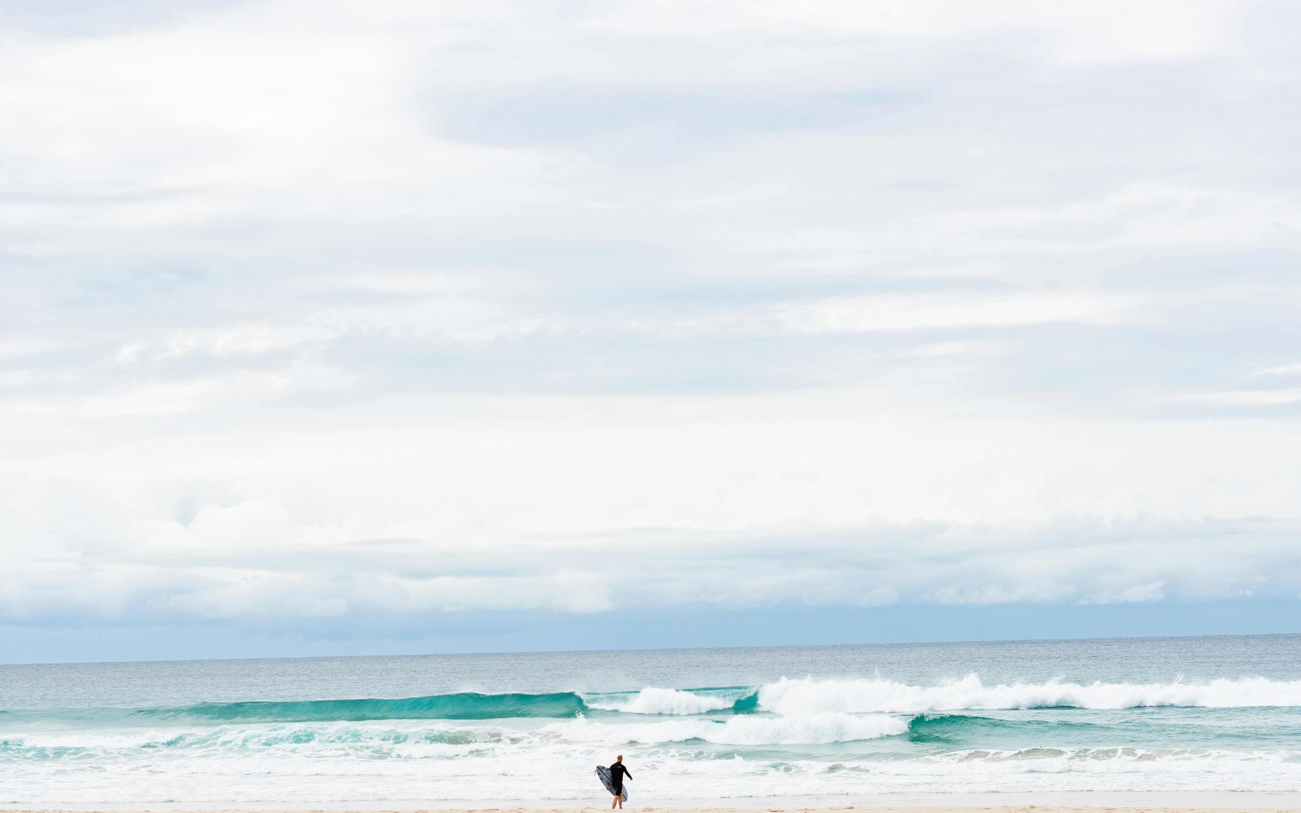 Solitary Surfer Beneath a Layered Morning Sky