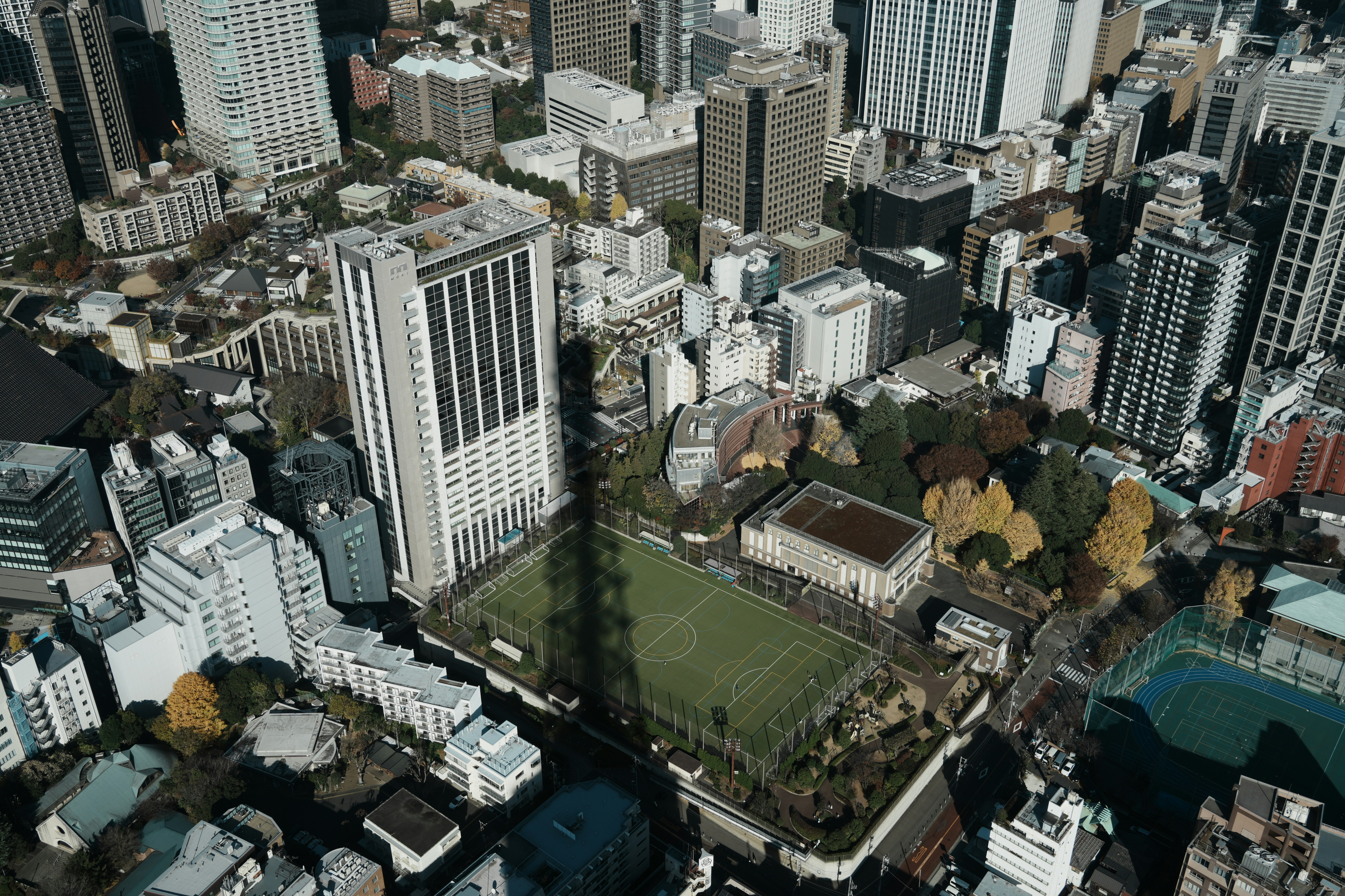 Aerial Spotlight: City Football Field Nestled Among Skyscrapers