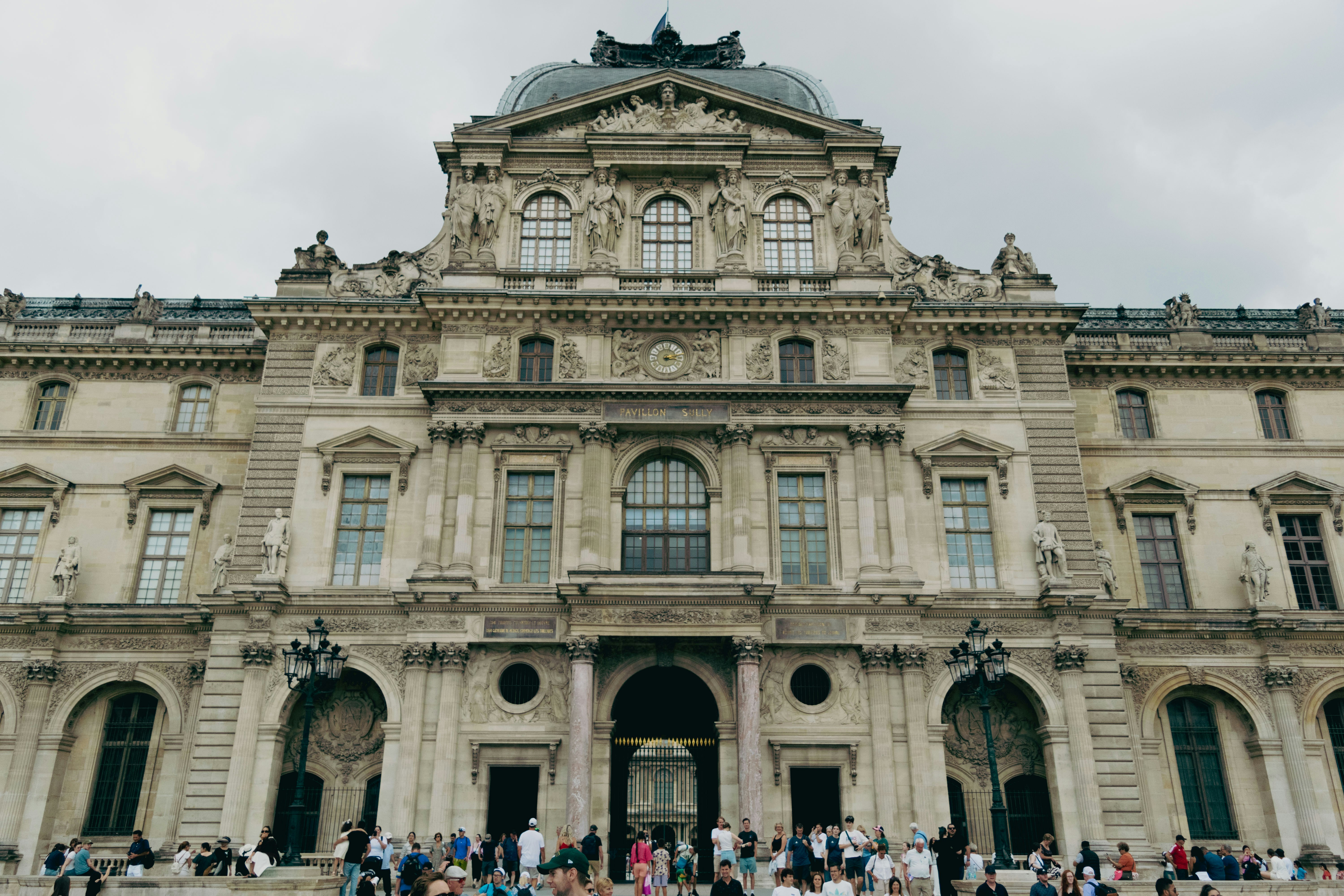 Faces at the Grand Facade: A Crowd Beneath the Monumental Arch
