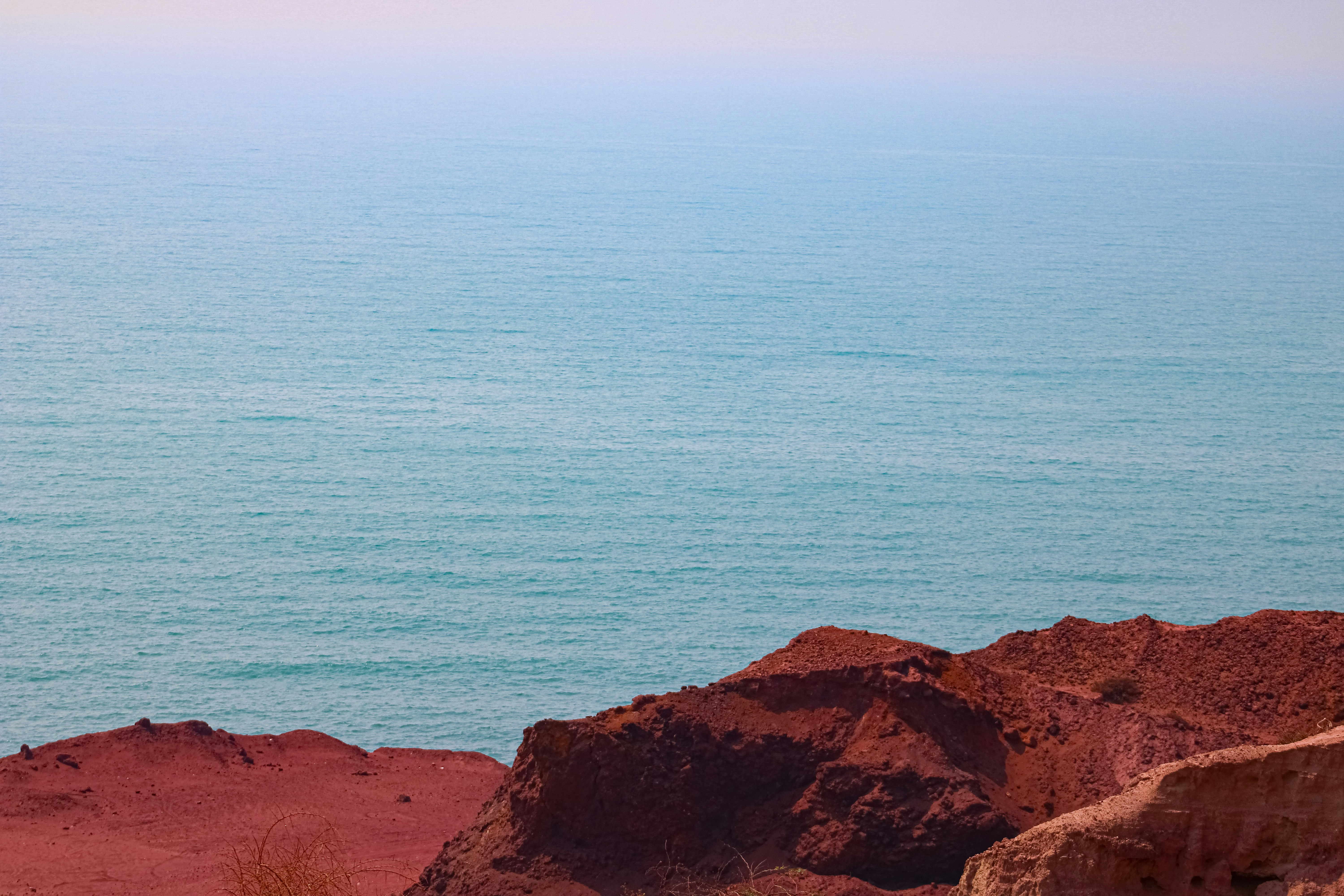 Reddish Cliff Edge Meeting the Quiet Sea