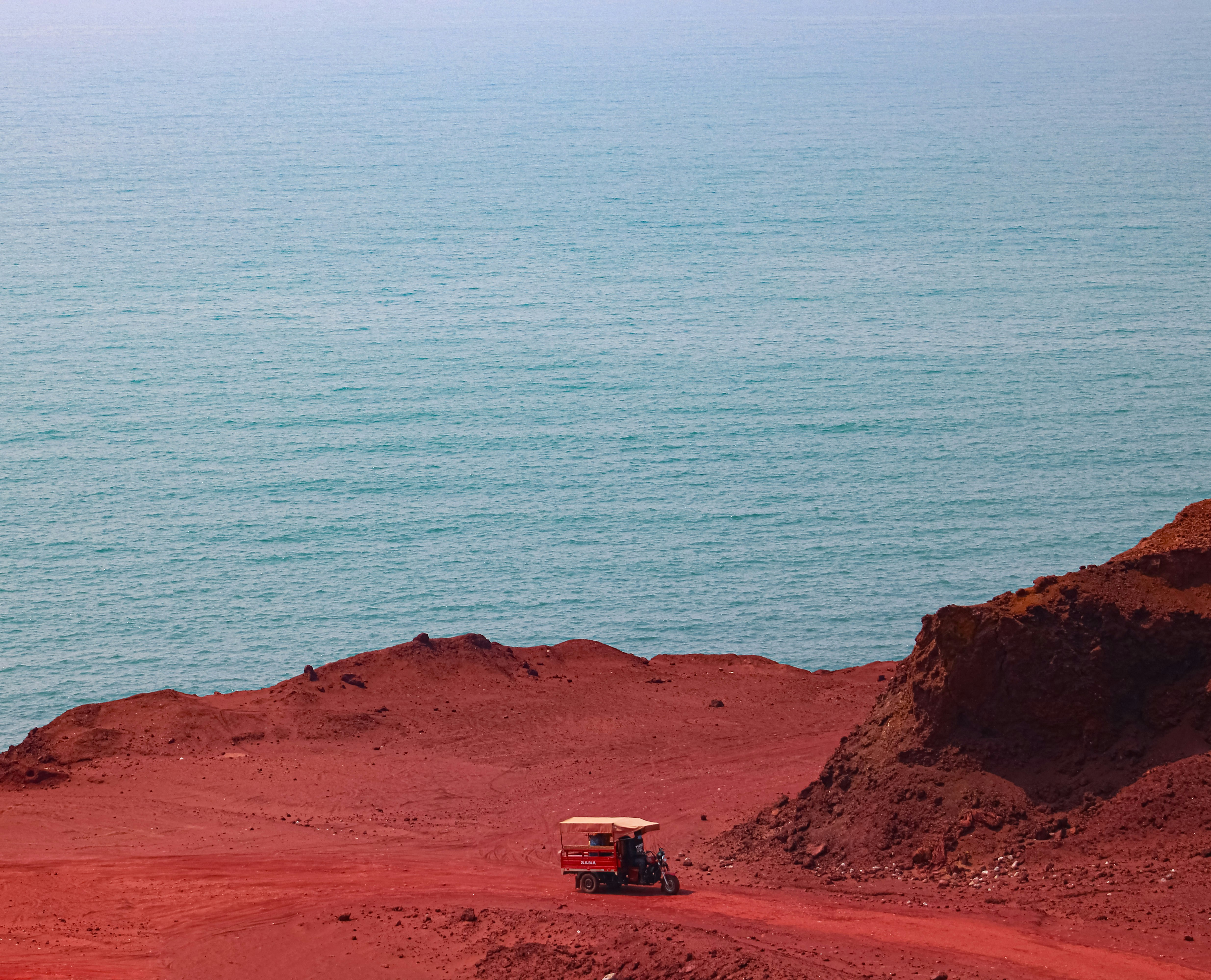 Red Earth, Blue Horizon: A Dump Truck on a Desolate Quarry Rim