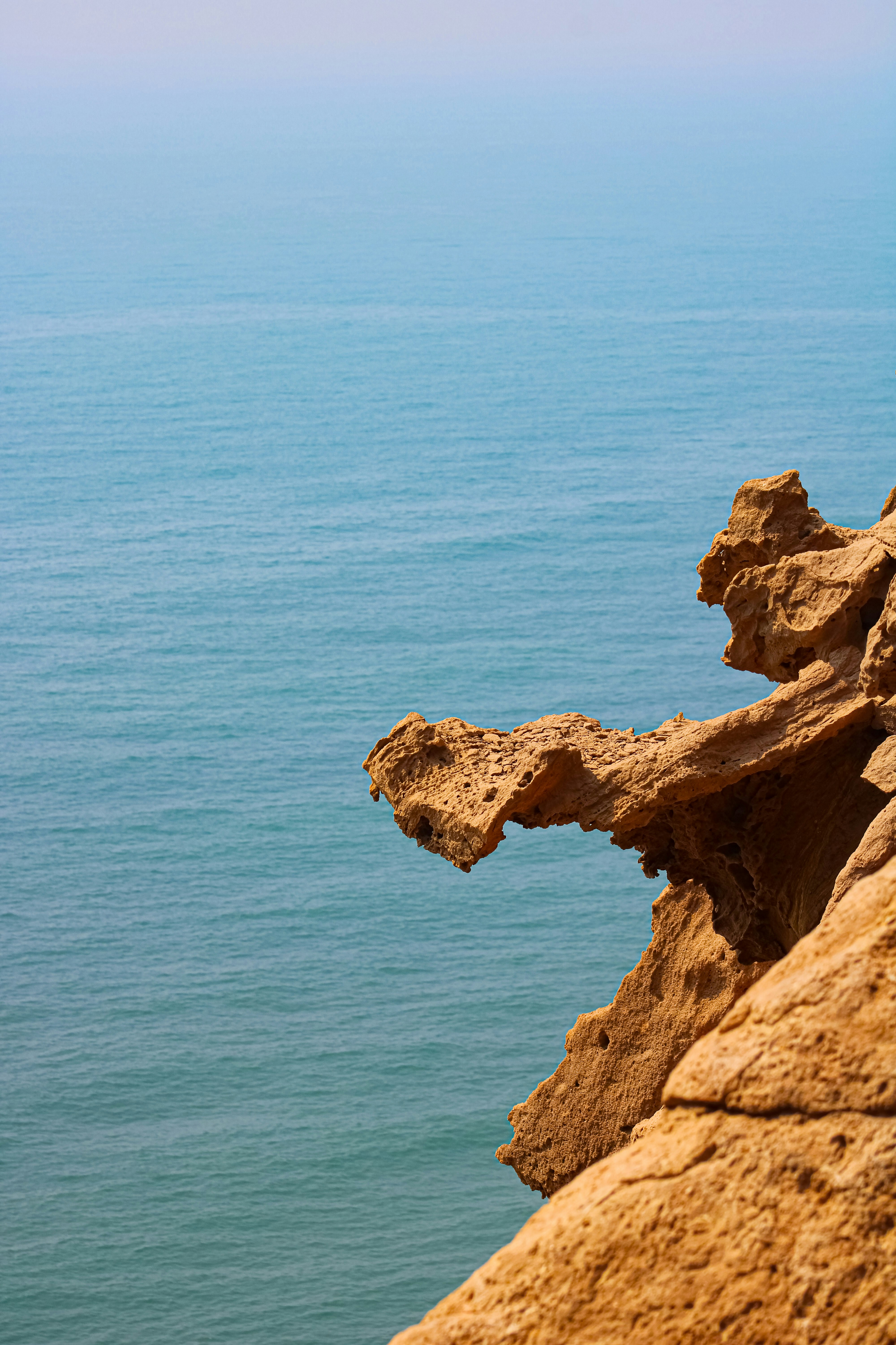 Erosion Edge over Icy Waters: A Rusted Cliff Protrudes into the Sea