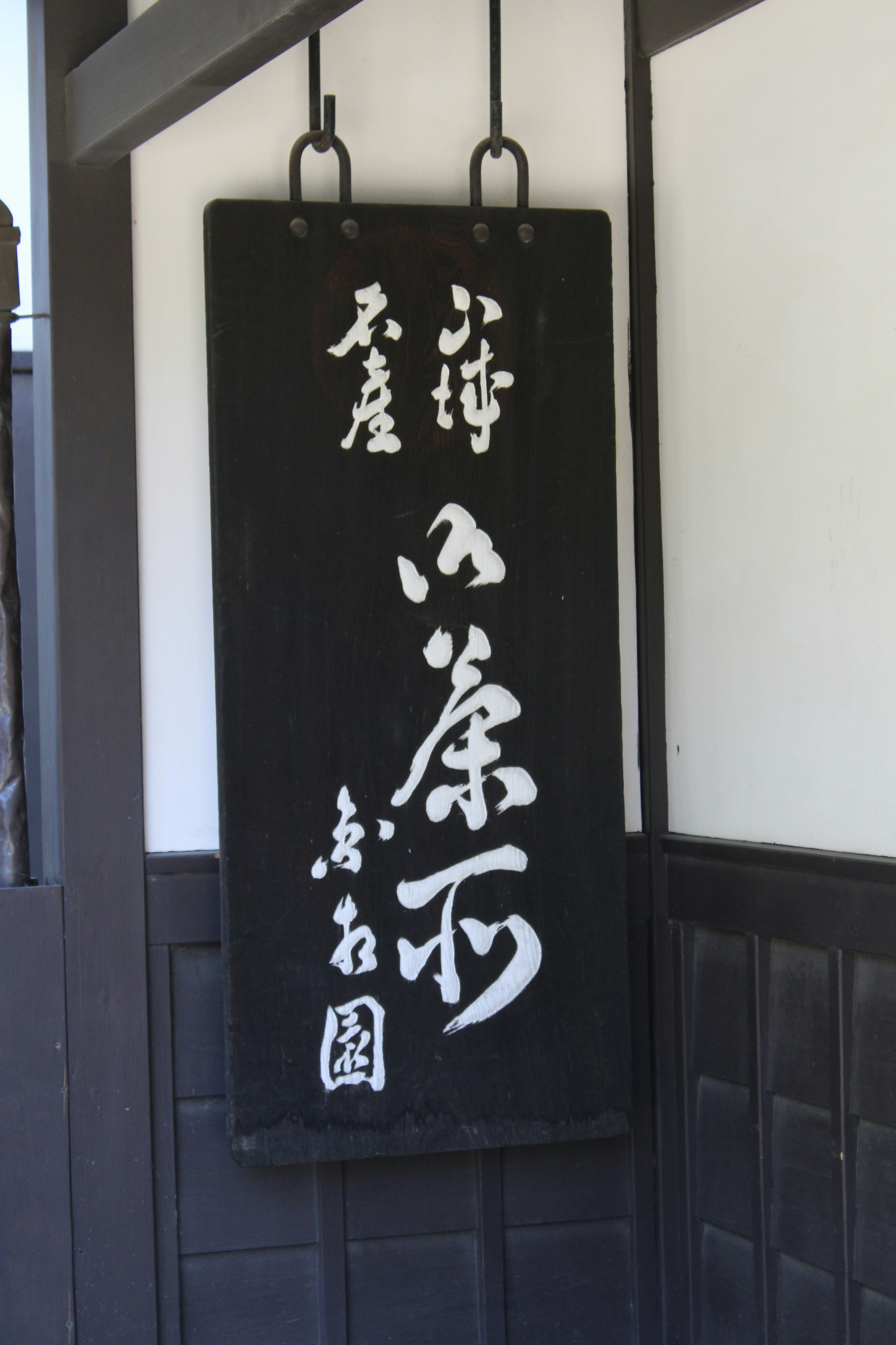 Vertical Wooden Signboard with White Calligraphy on Dark Panel