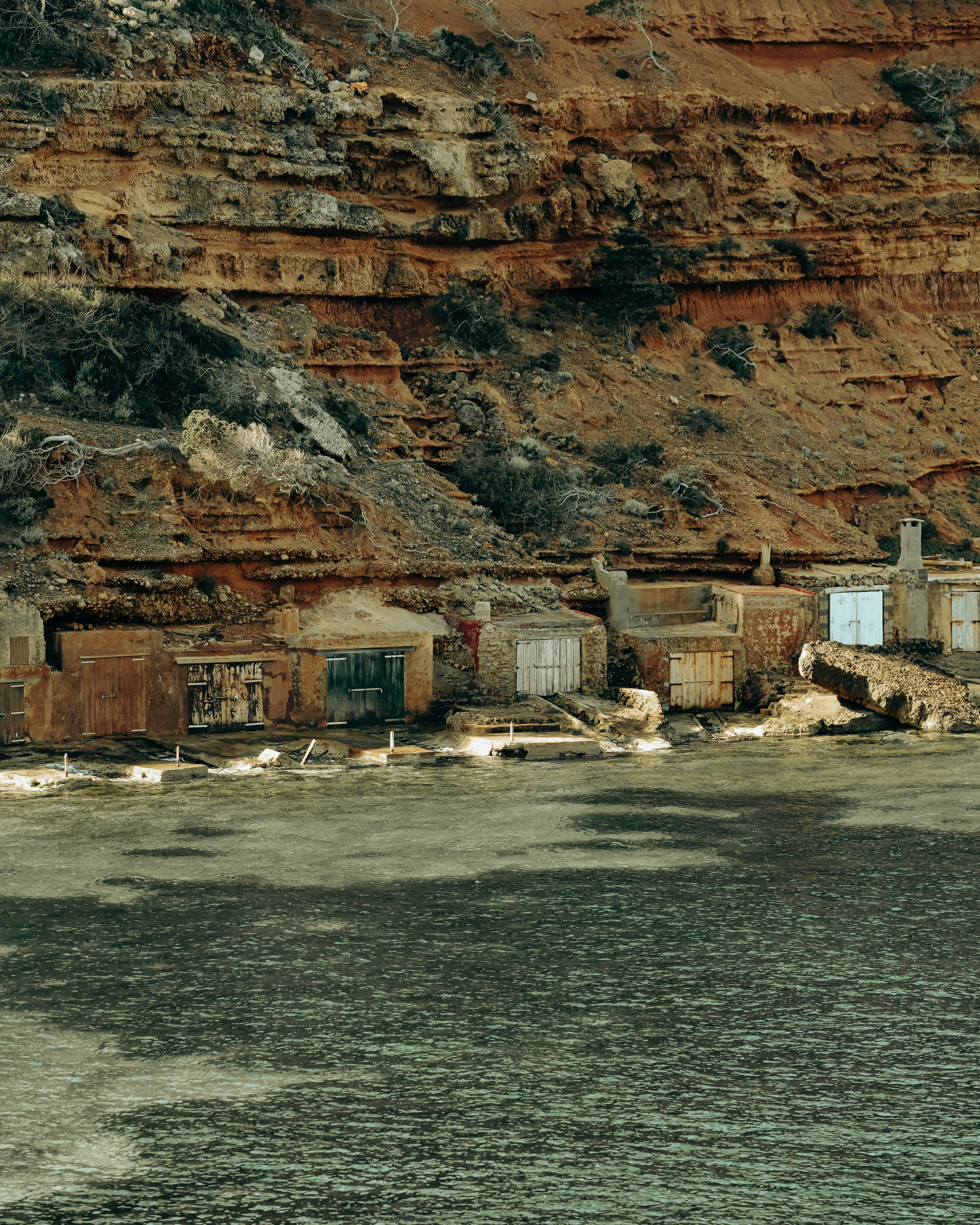 Weathered harbor ruins cling to a rugged cliffside