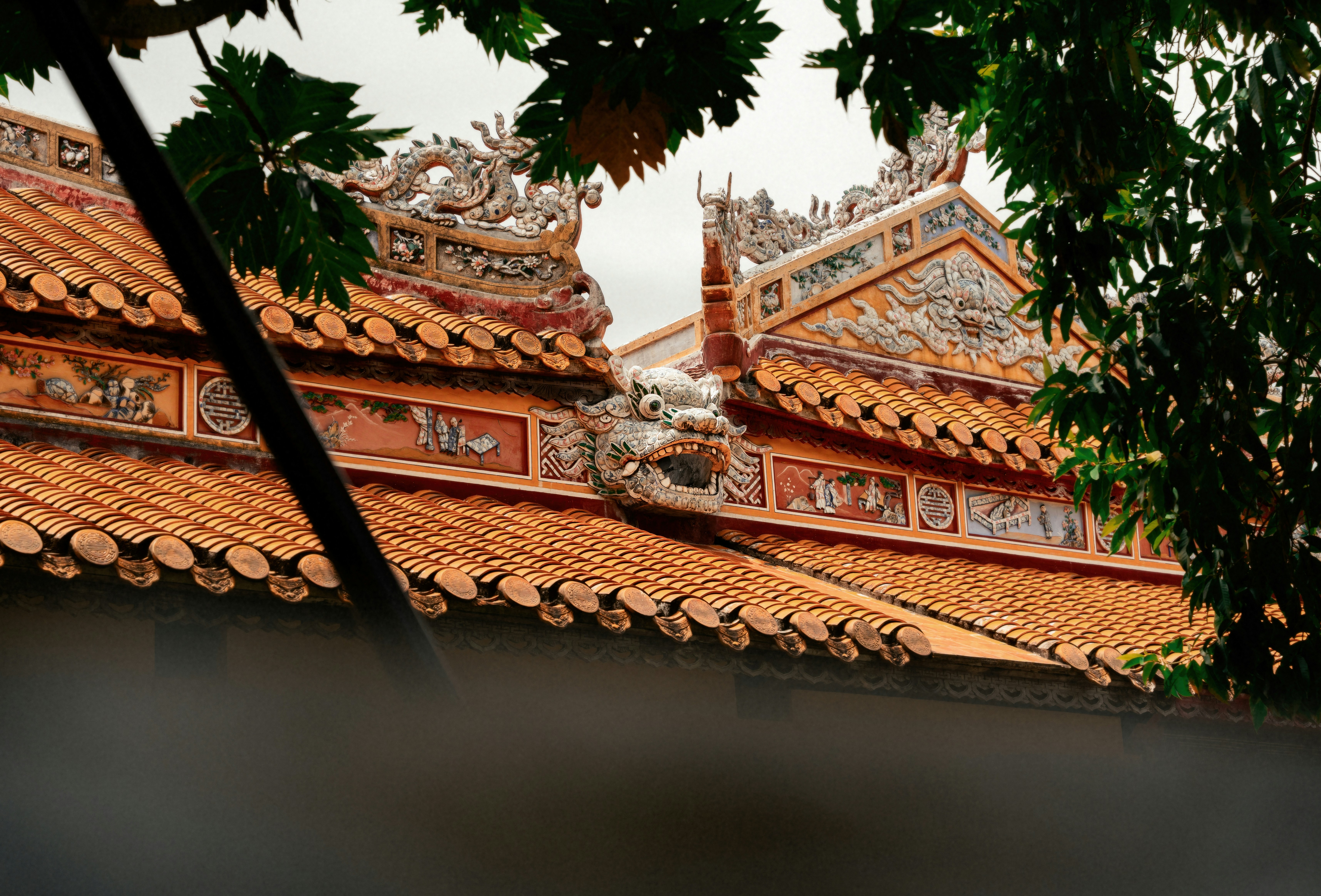 Dragon Crest Over Tiles: An Architectural Moment Framed by Foliage