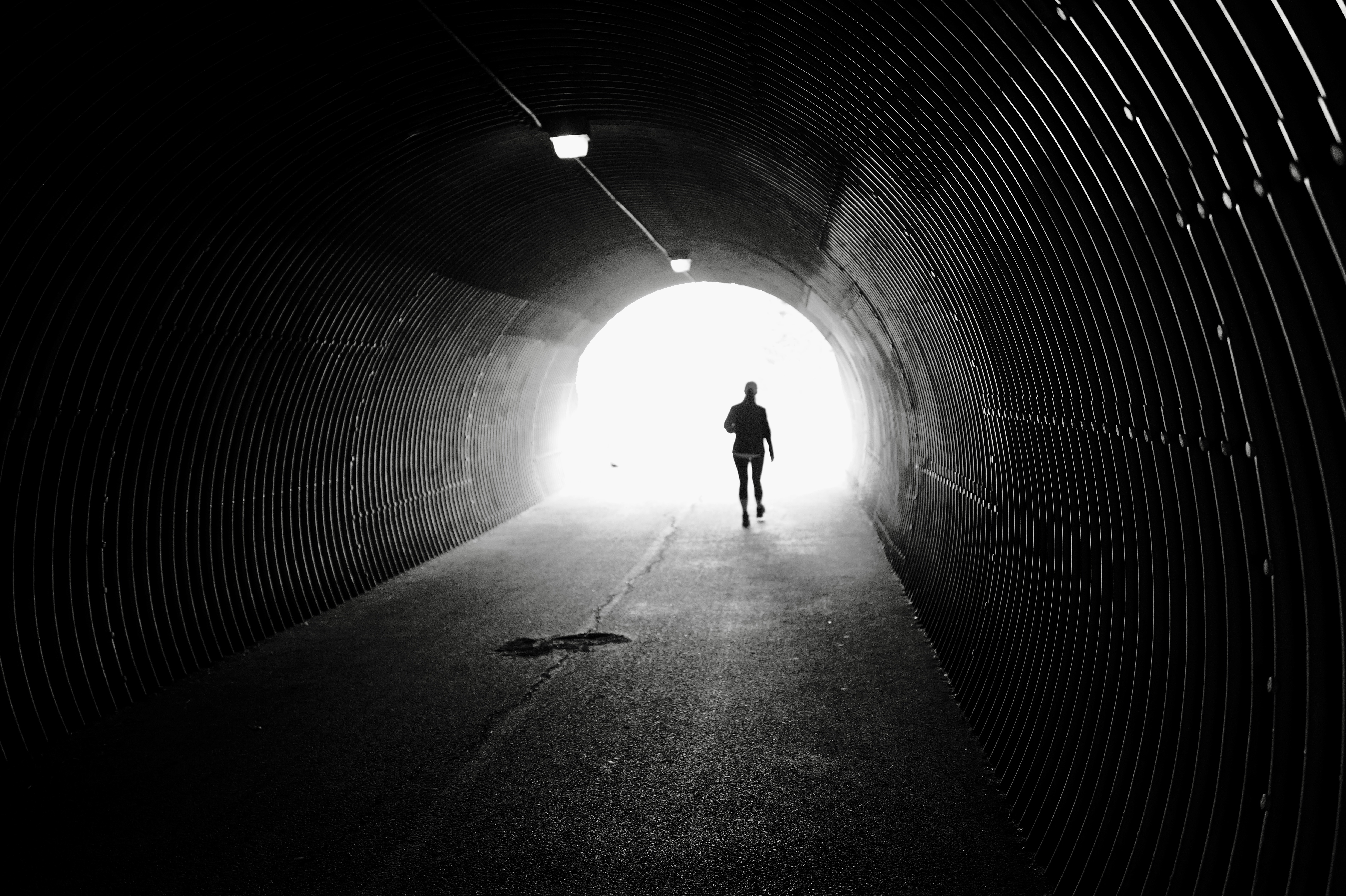 Silhouette in the Light: A Figure Emerges from the Tunnel