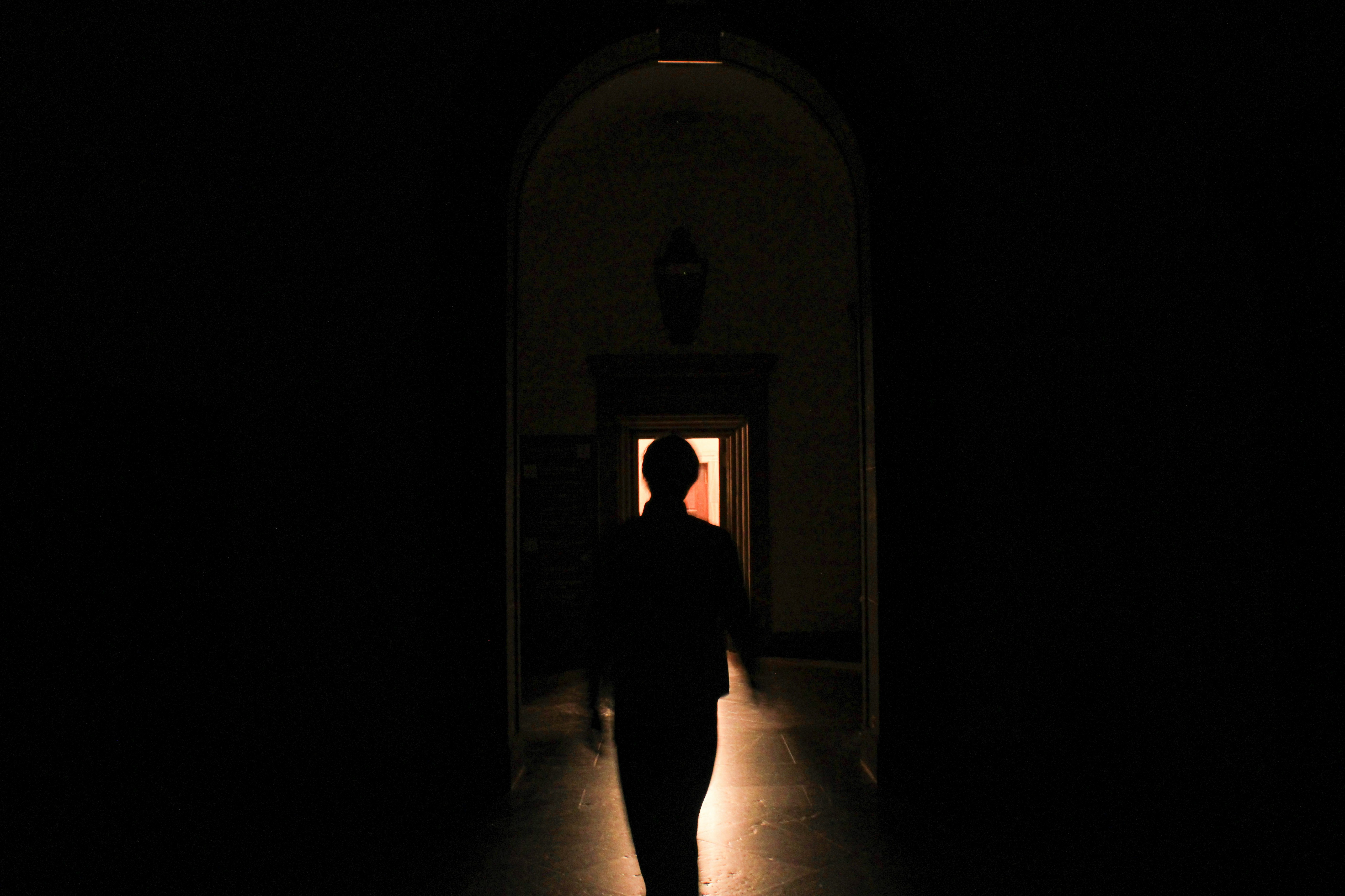 Silhouette at the Threshold: A Figure Steps into a Dim Corridor