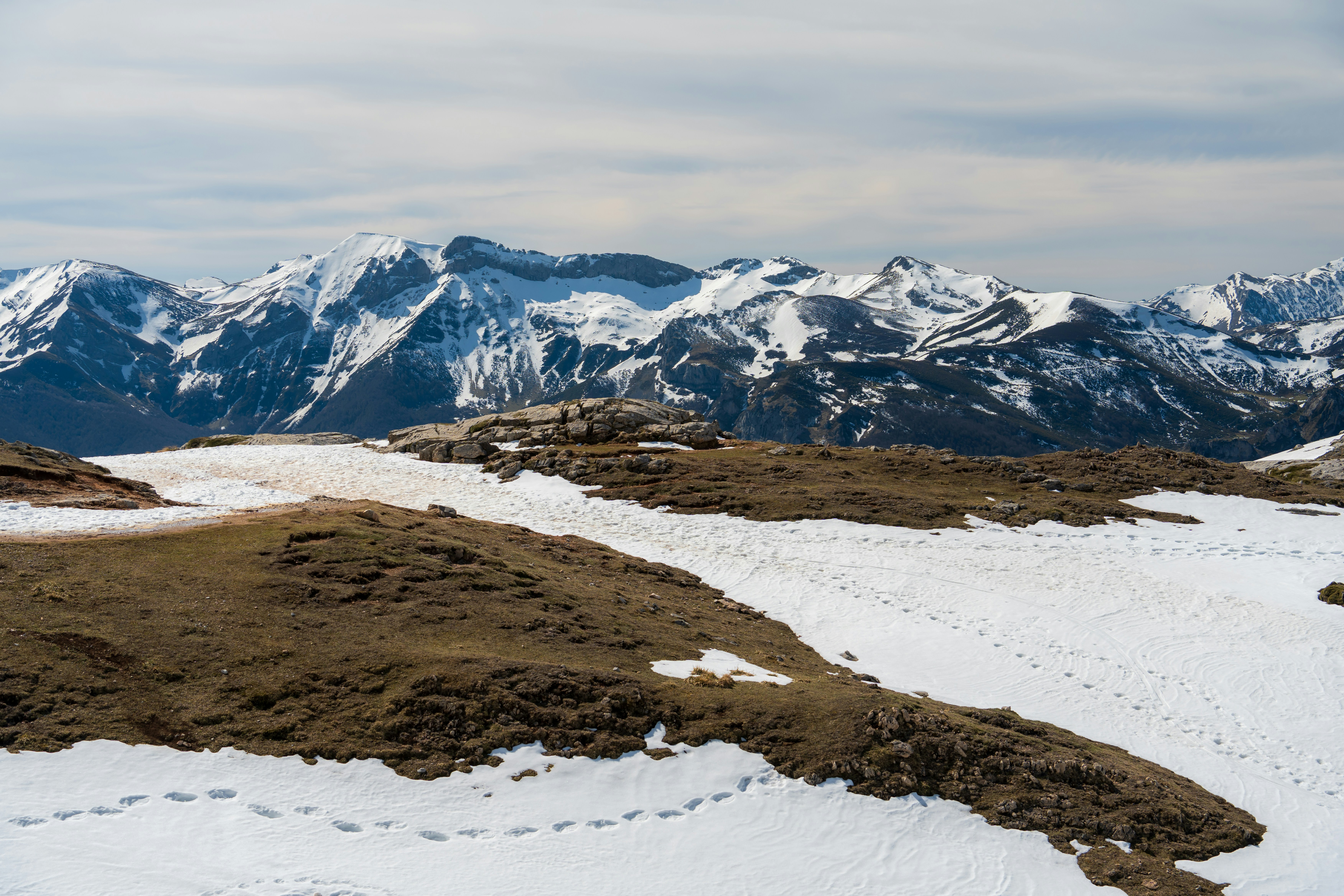 Snow-dusted ridges and distant Alps under a calm sky