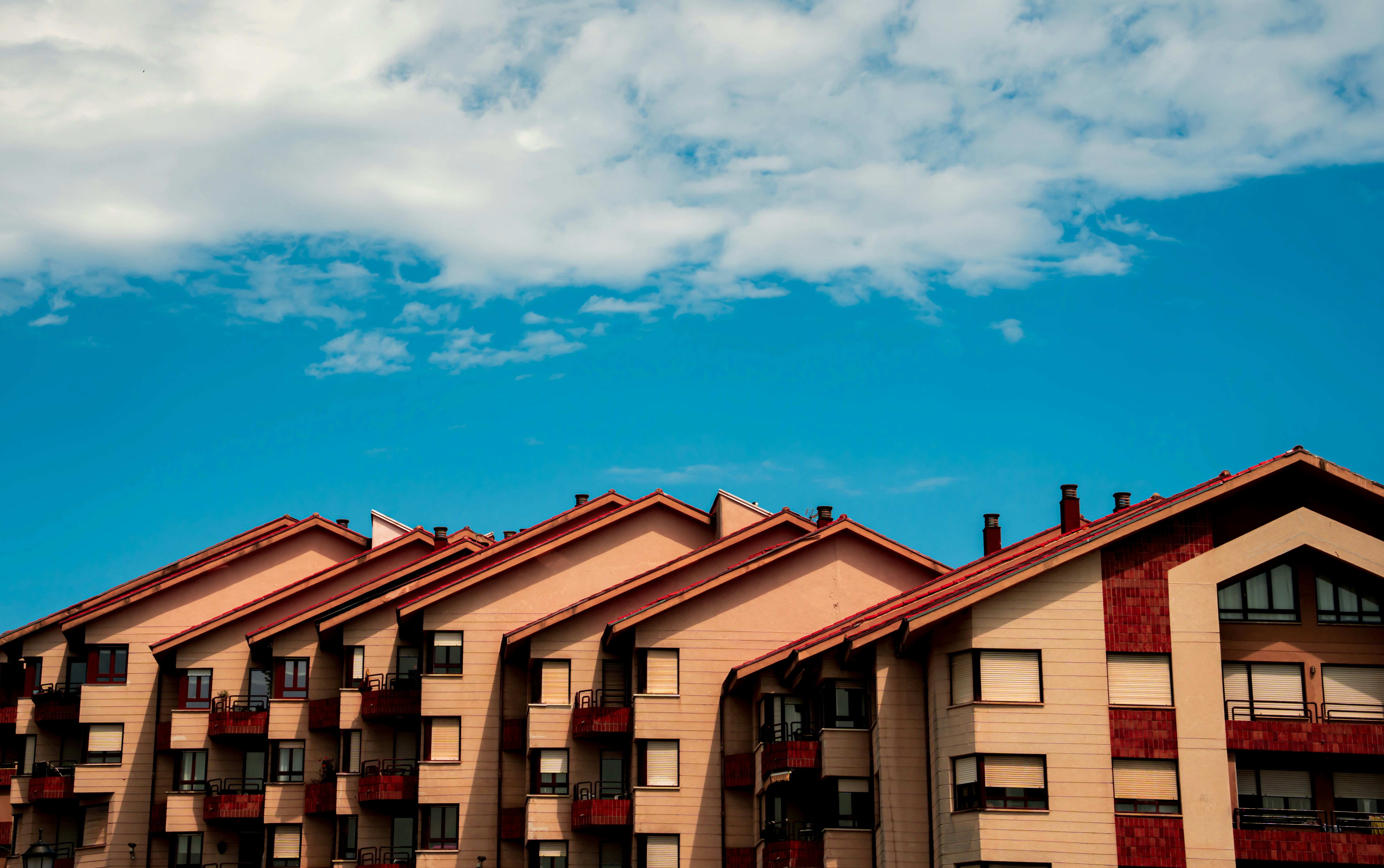 Row of terracotta-roofed apartments under a vivid blue sky
