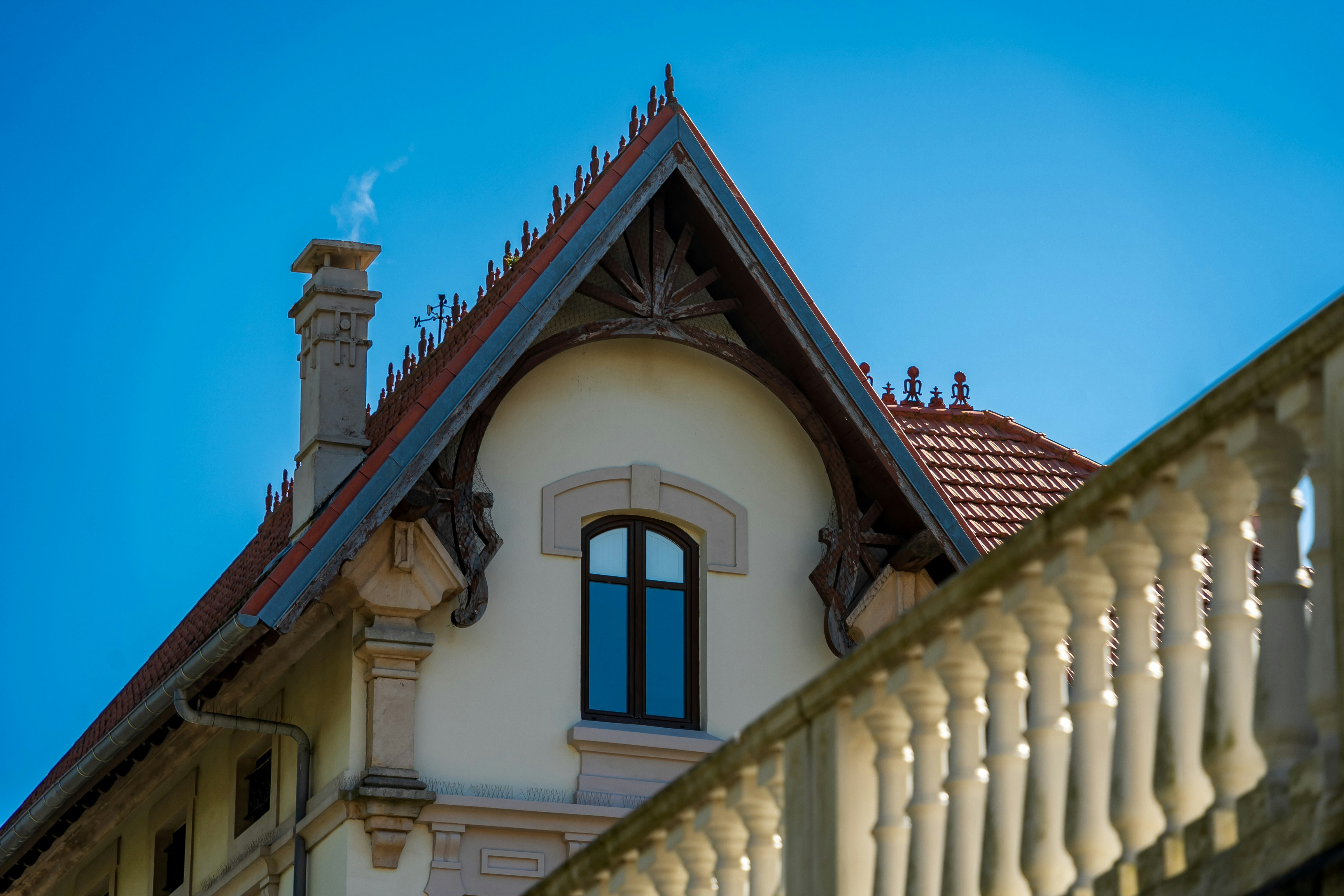 Gabled Roofline and Balcony Spires against a Bright Sky