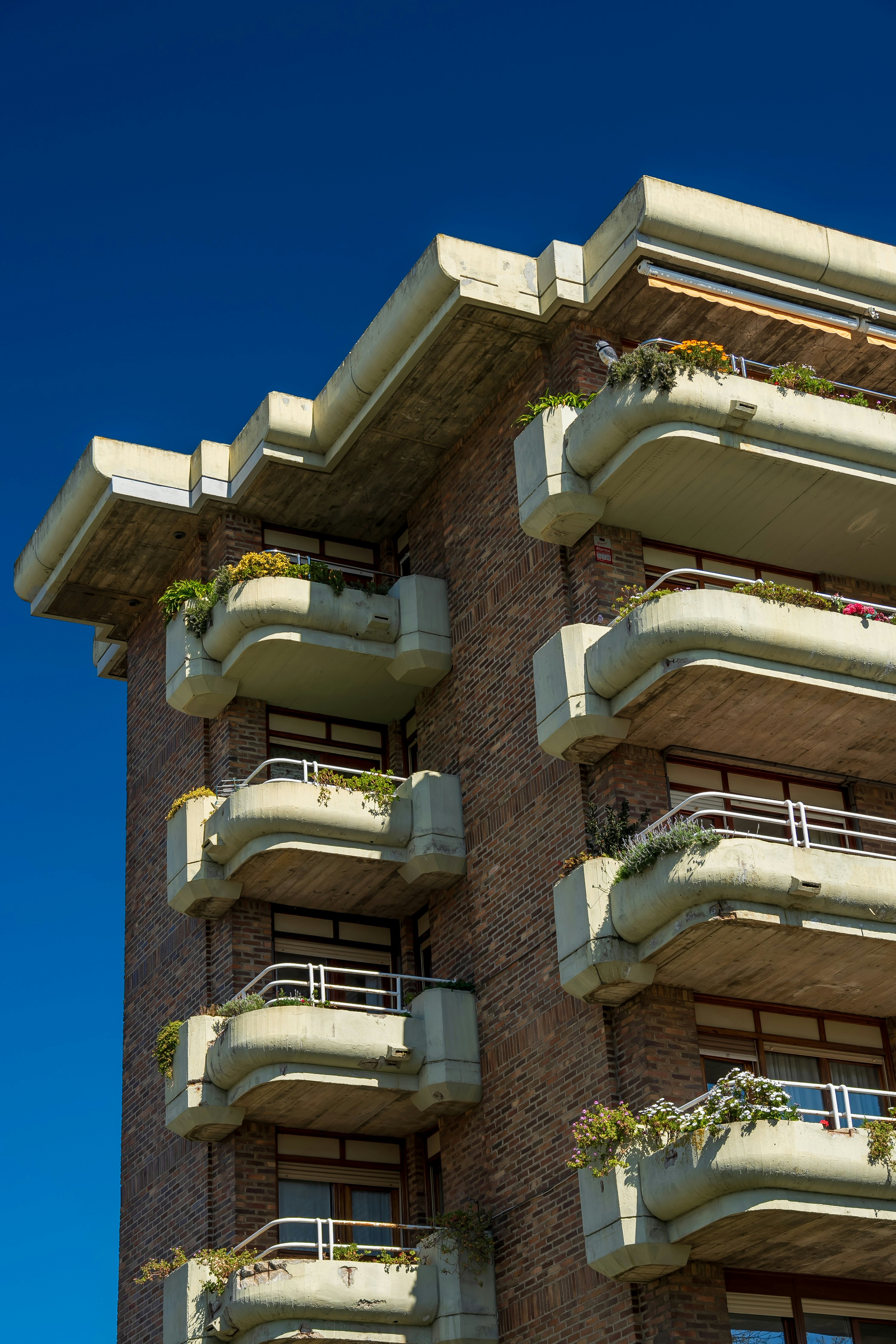 Concrete balconies reach toward the blue: a brick apartment stacks its curves