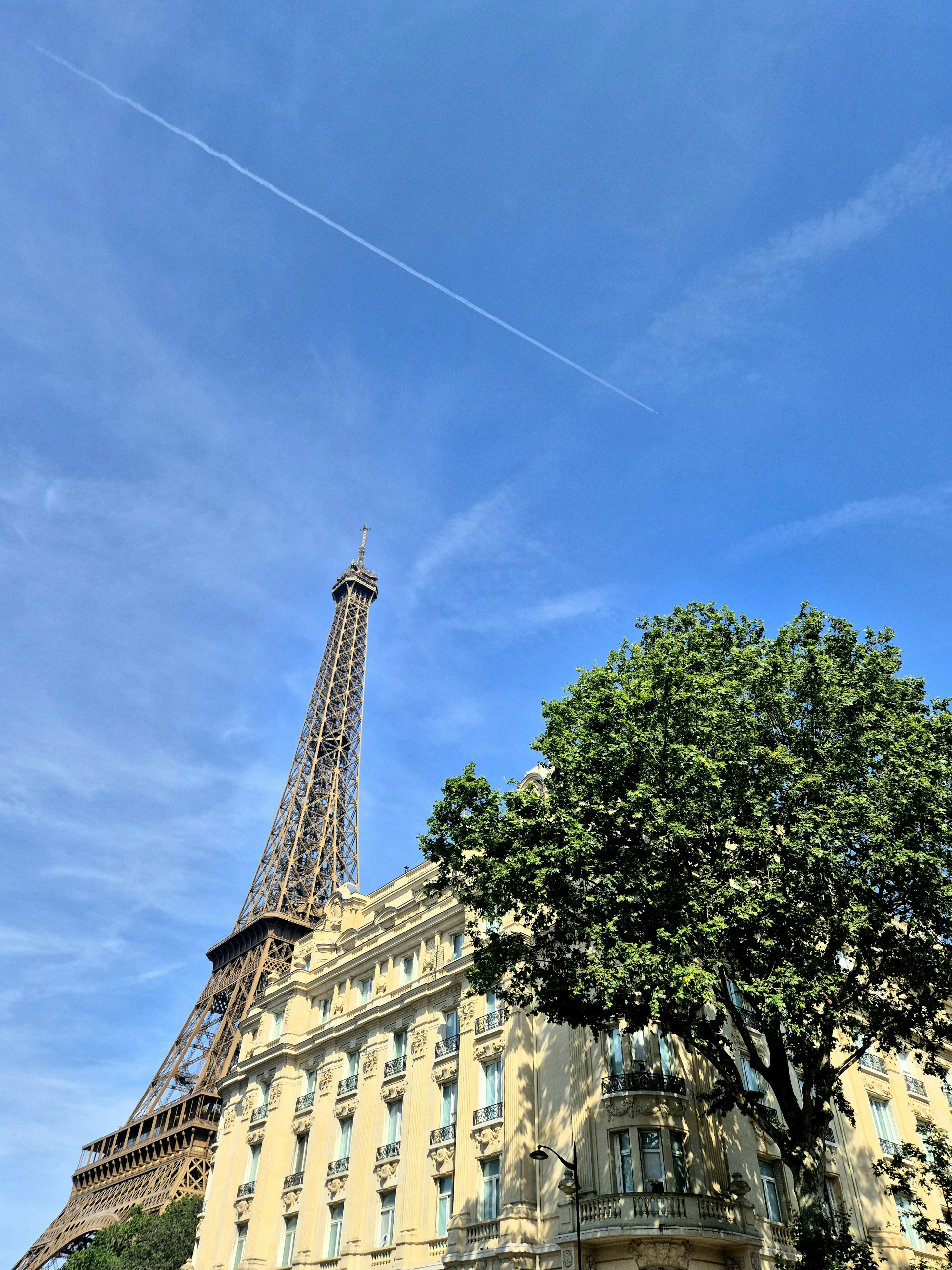 Eiffel meets avenue charm: tower peeking above Parisian facades