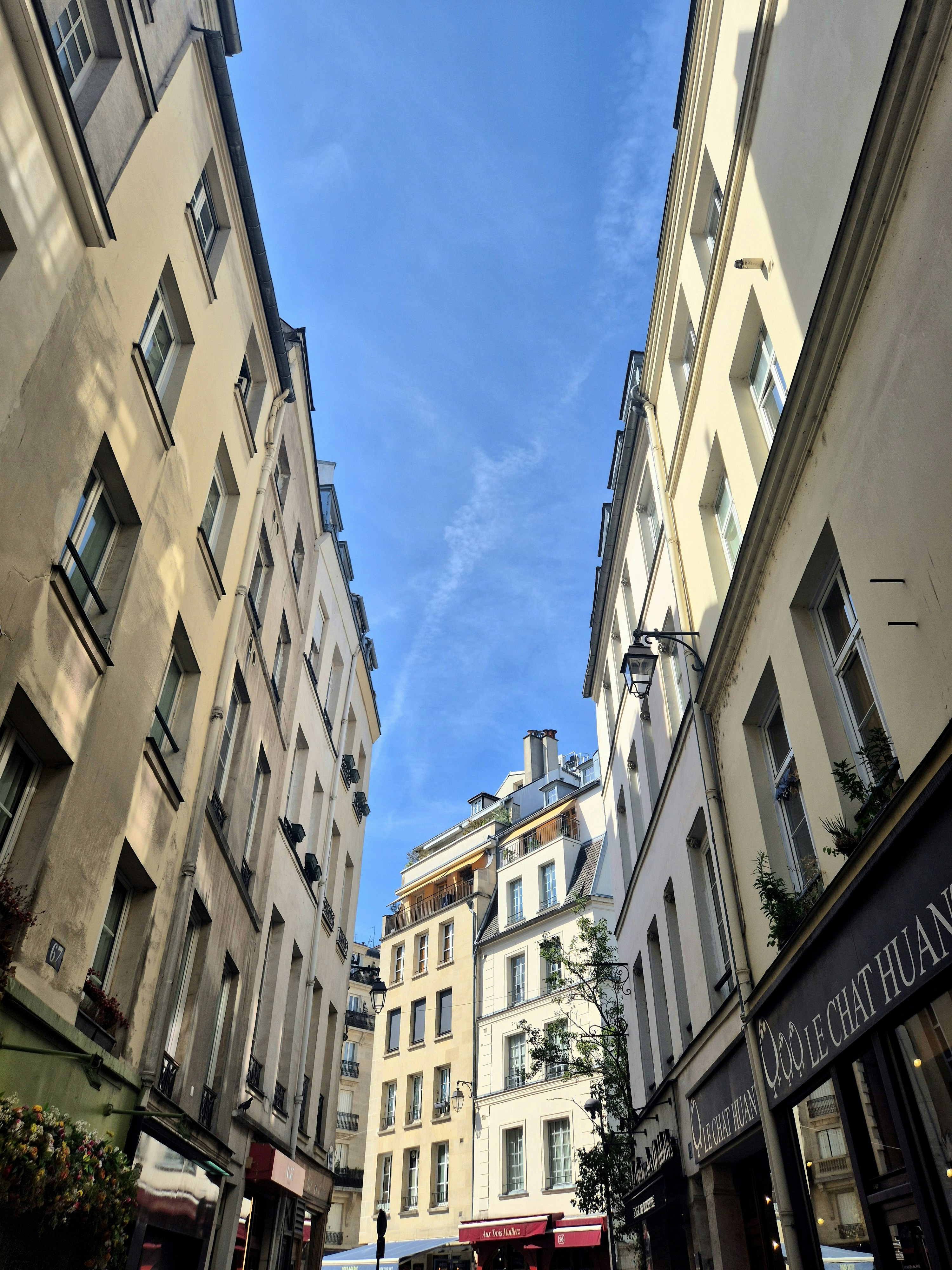 Skyward Alley: Narrow Parisian Facades Frame a Bright Blue Sky