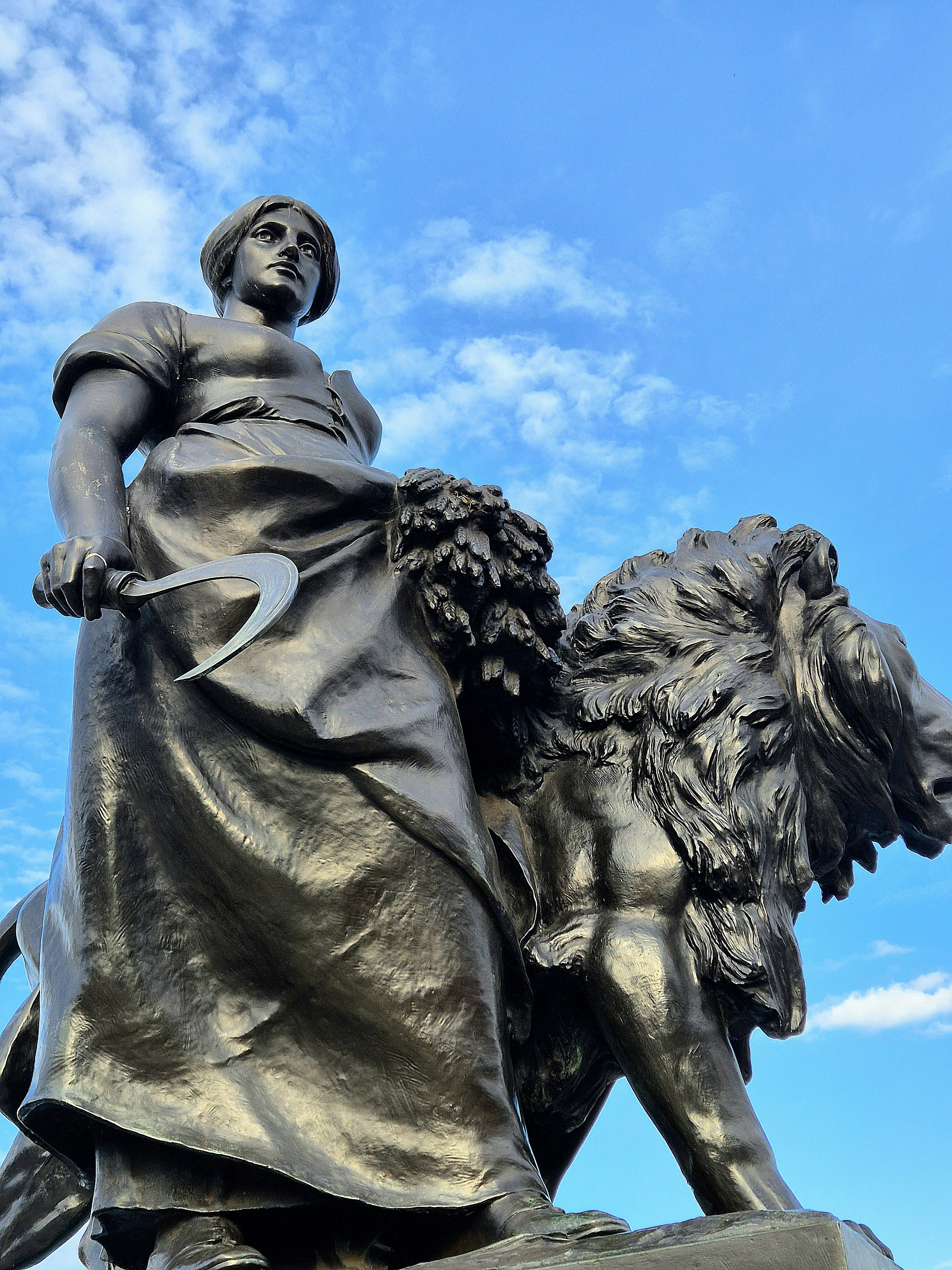 Stone Sentinel: A Female Figure With Scythe and Winged Companion
