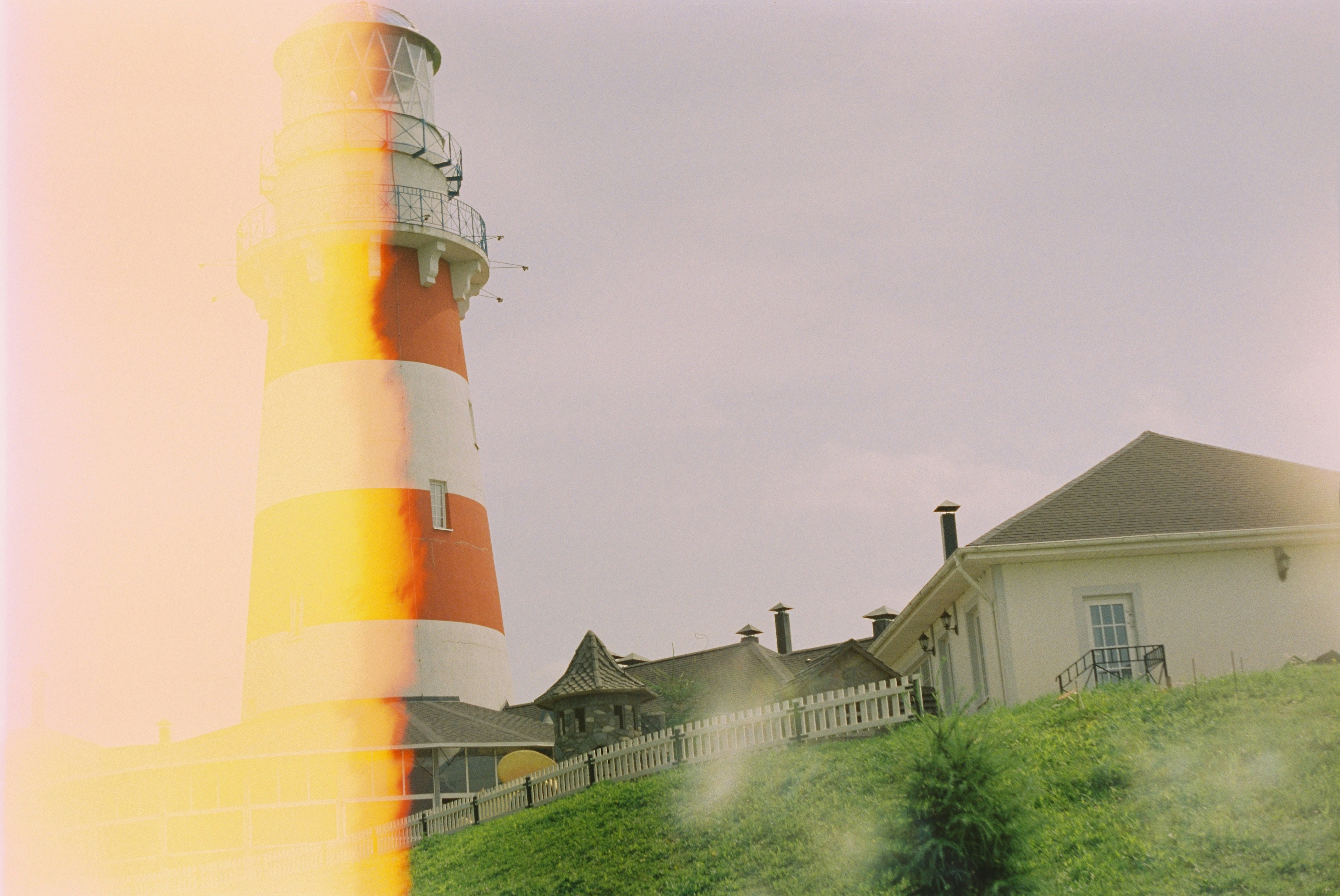 Striped Beacon by the Sea: A Lighthouse Portrait with Soft Coastline Blur