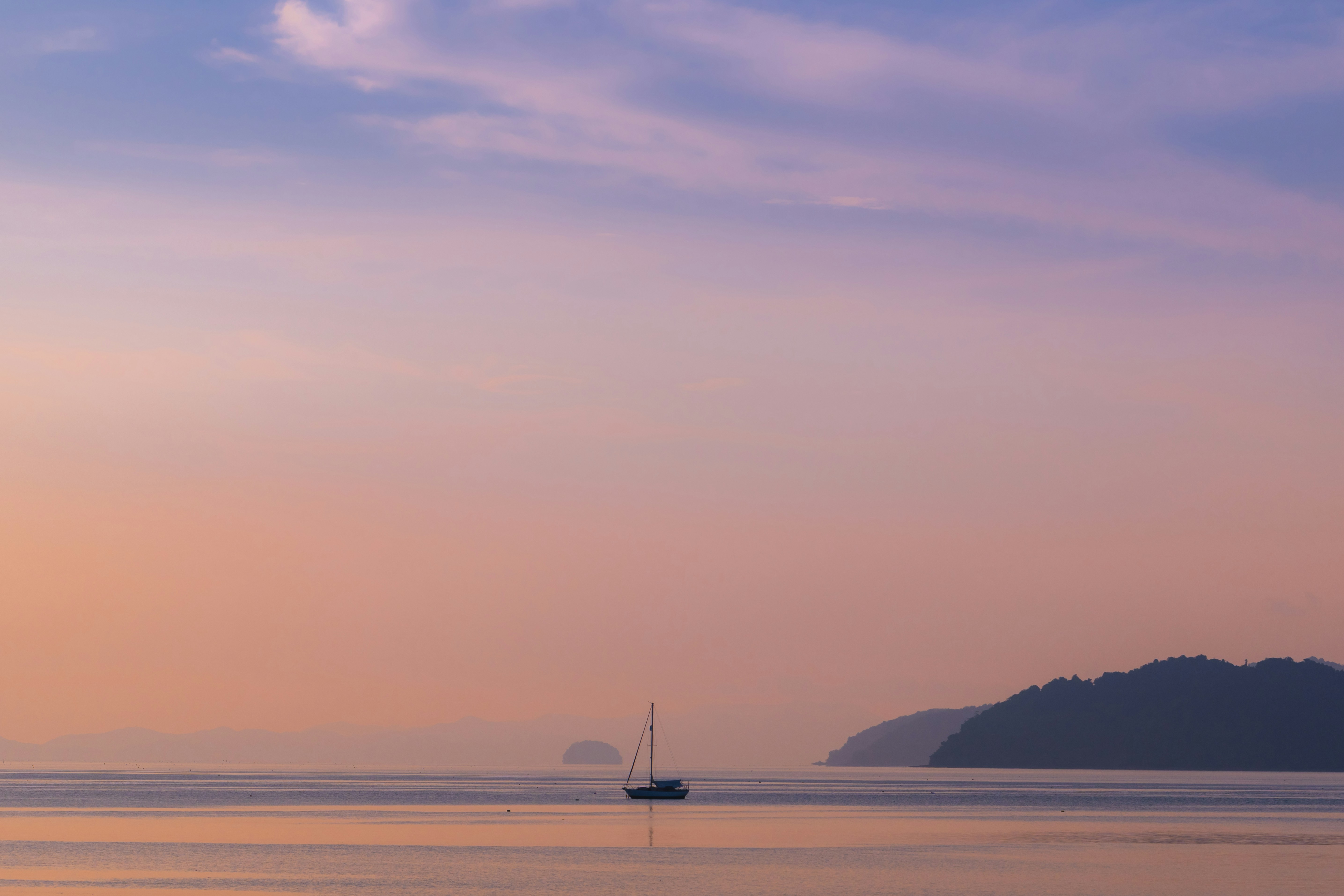 Hushed Sea: A Sailboat at Dusk Beyond the Distant Headland