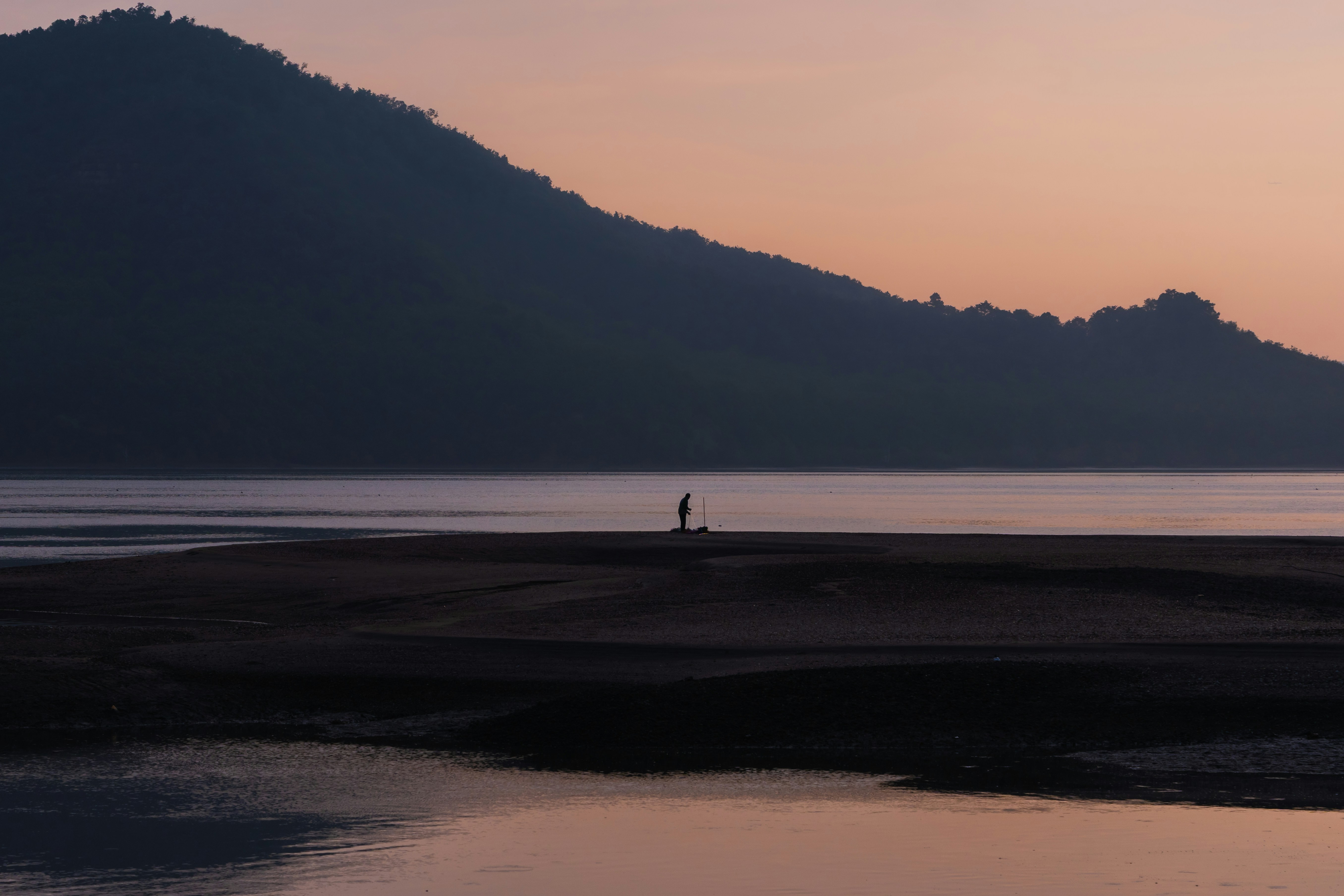 Silhouette at Dusk: A Lone Figure on Quiet Shore