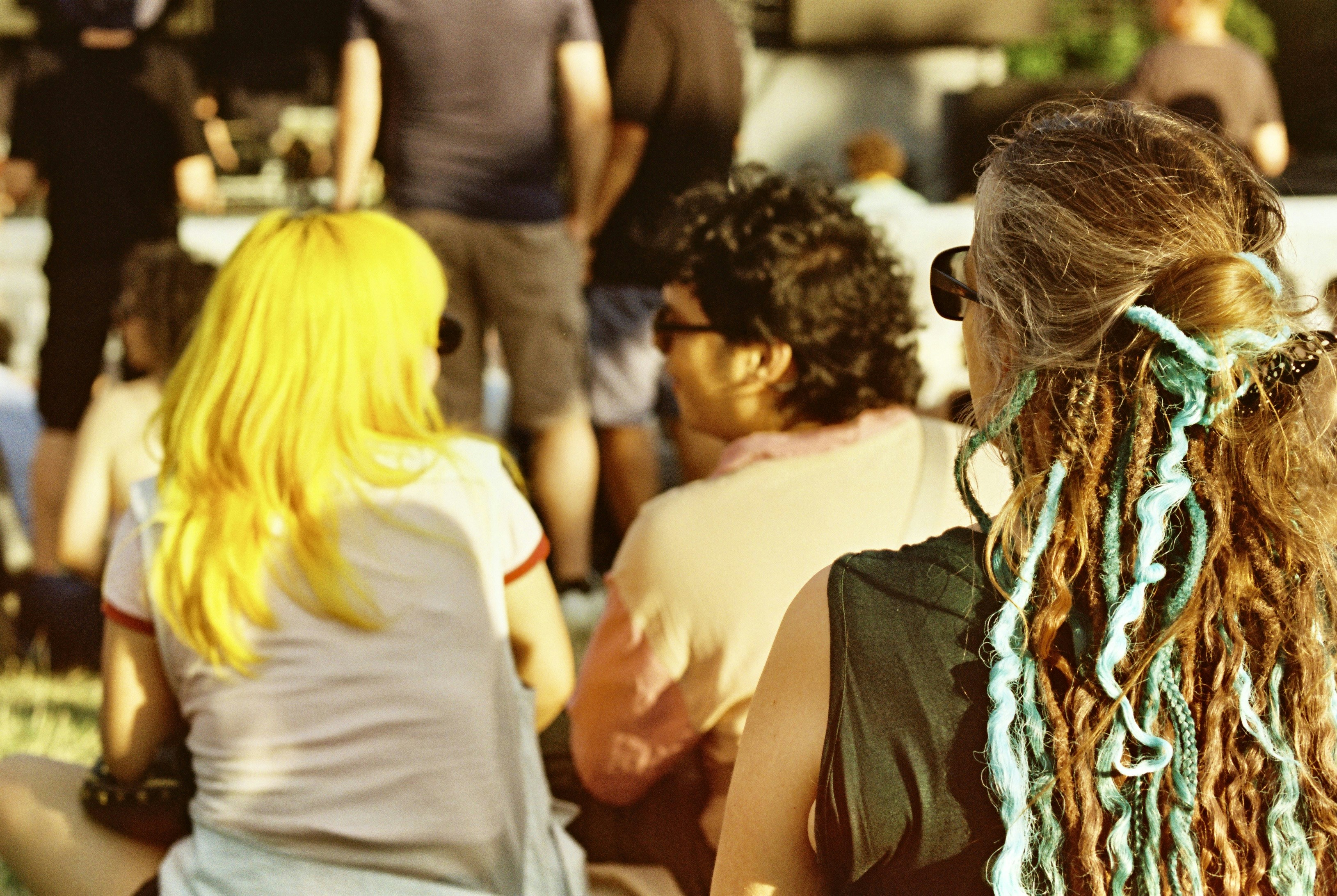Two Friends in a Sunlit Crowd: Back of Heads and Colorful Hair