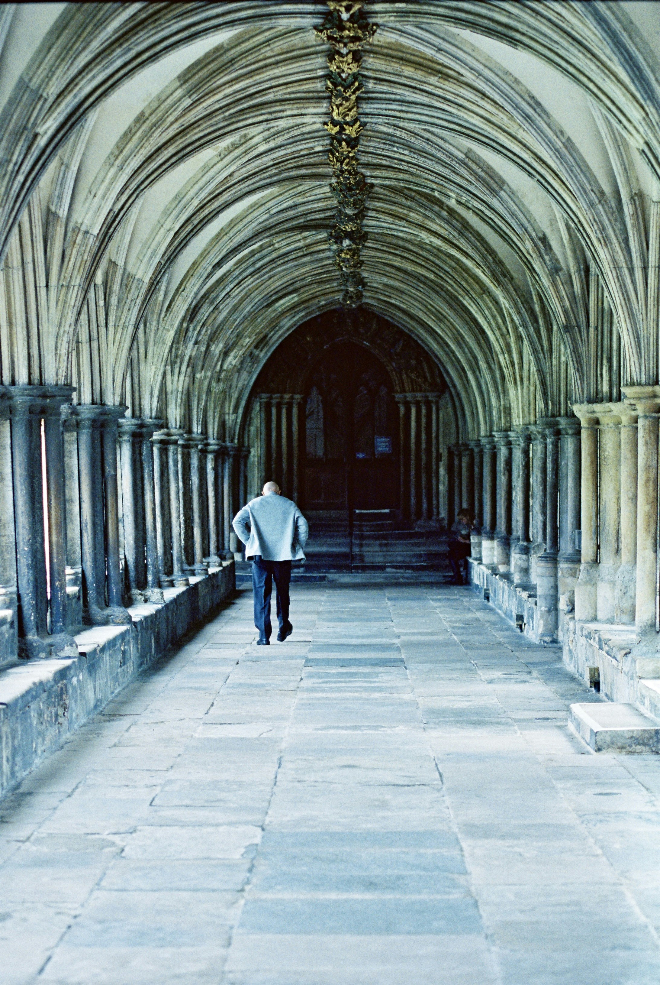 Walking the Gothic Corridor: A lone figure under stone arches