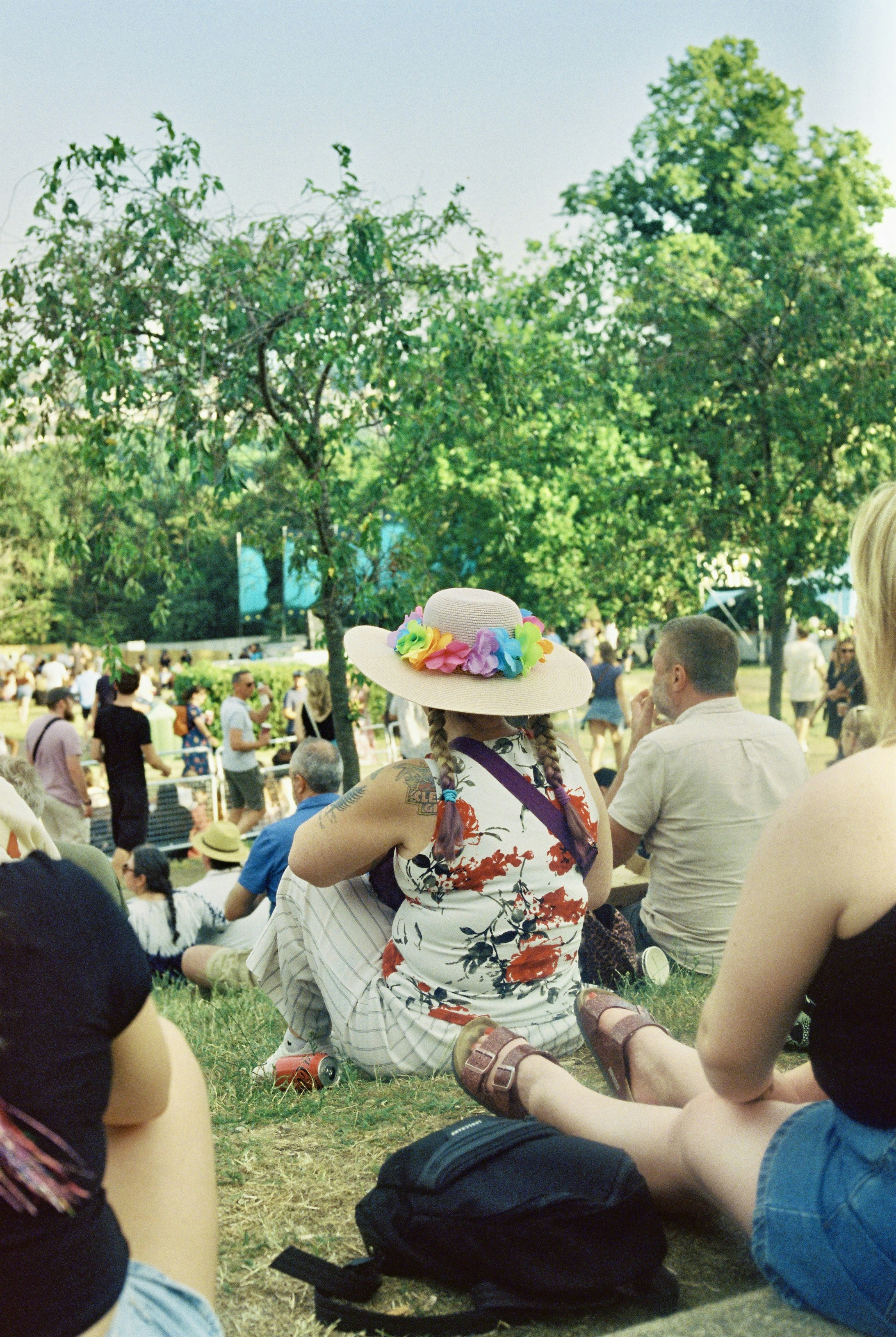 Sunlit Crowd: Floral Hat and Relaxed Gathering in the Park
