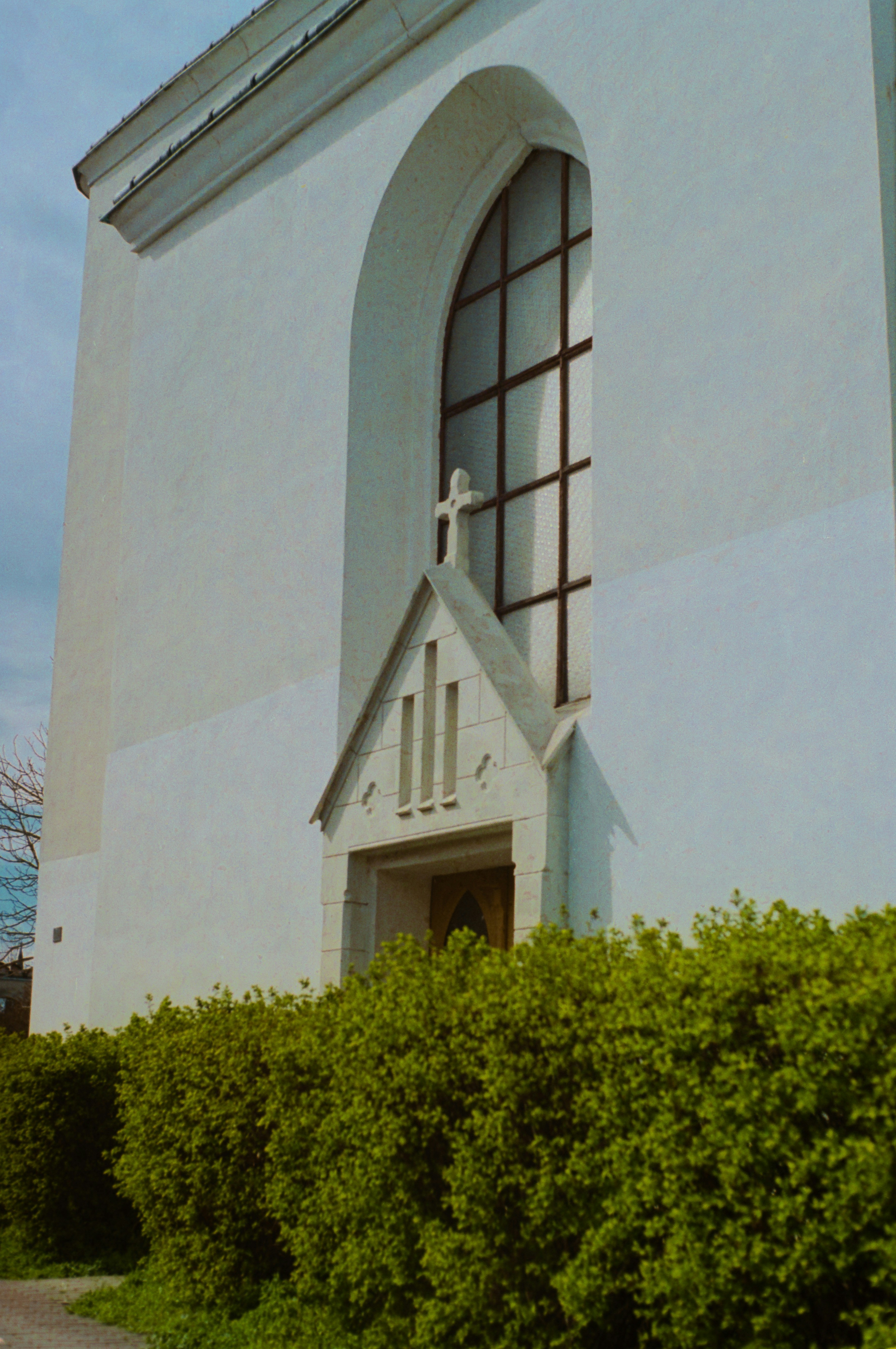 Arched Window Cathedral: A White Facade Framed by Green Hedge