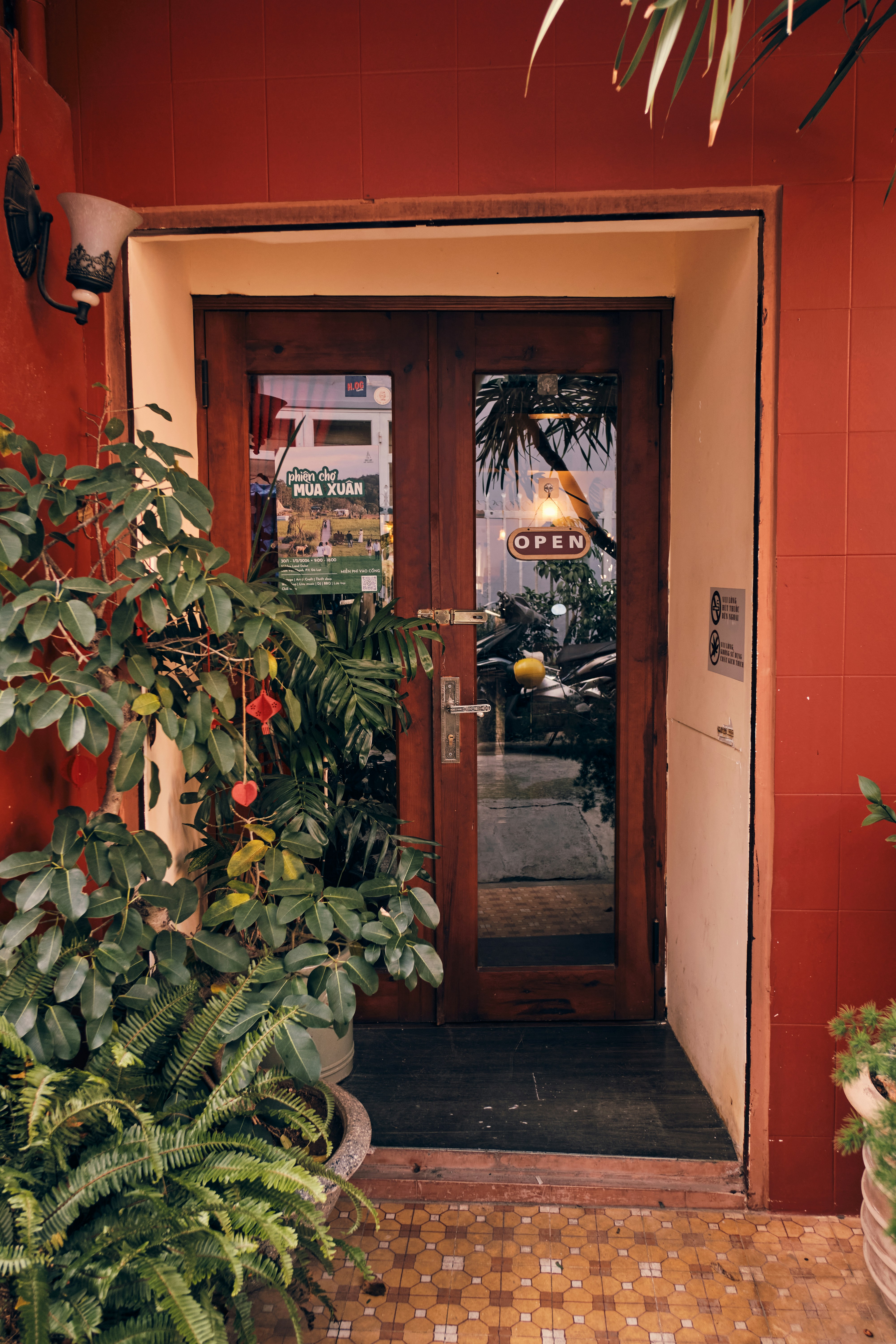 Open Sign, Closed Door, Greenery: A Quiet Threshold by a Red-Walled Entrance