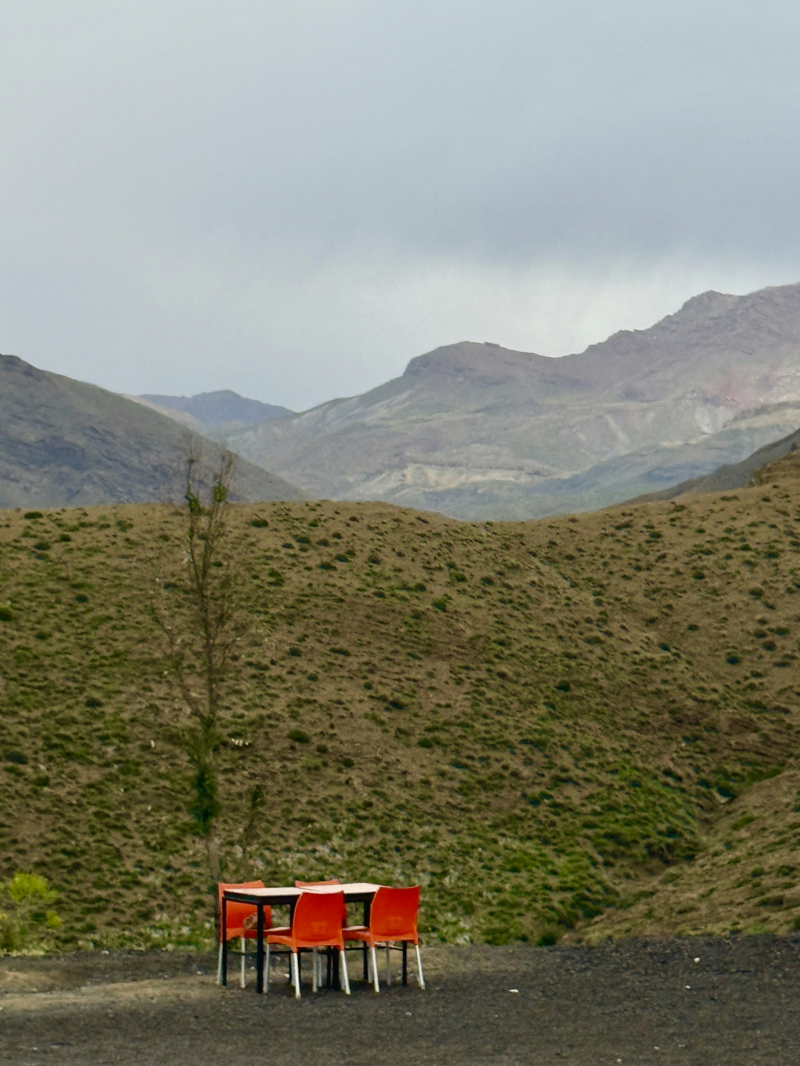 Desert hillside with bright orange chairs under a soft sky