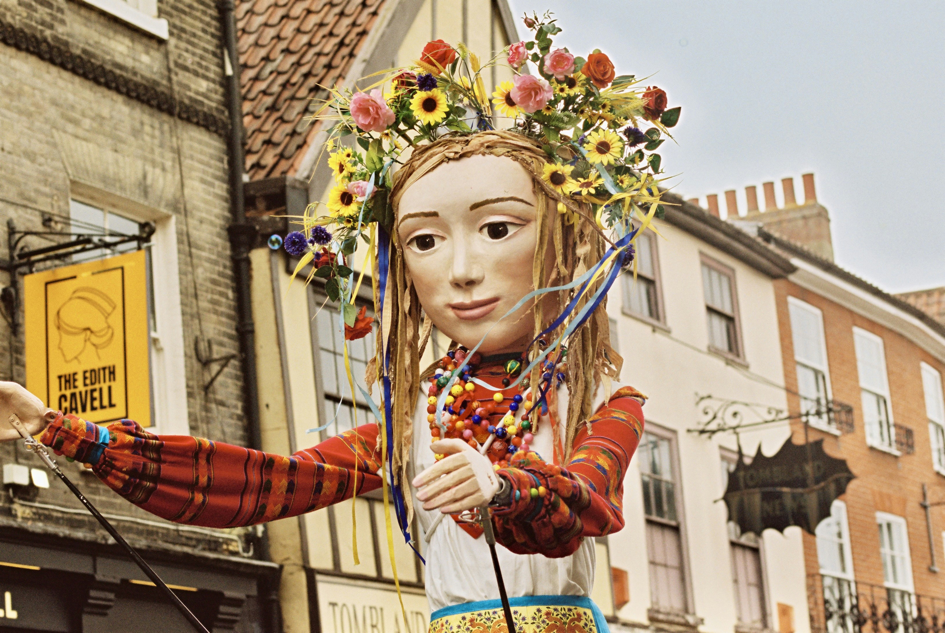 Floral Diademed Figure Adrift Above the High Street