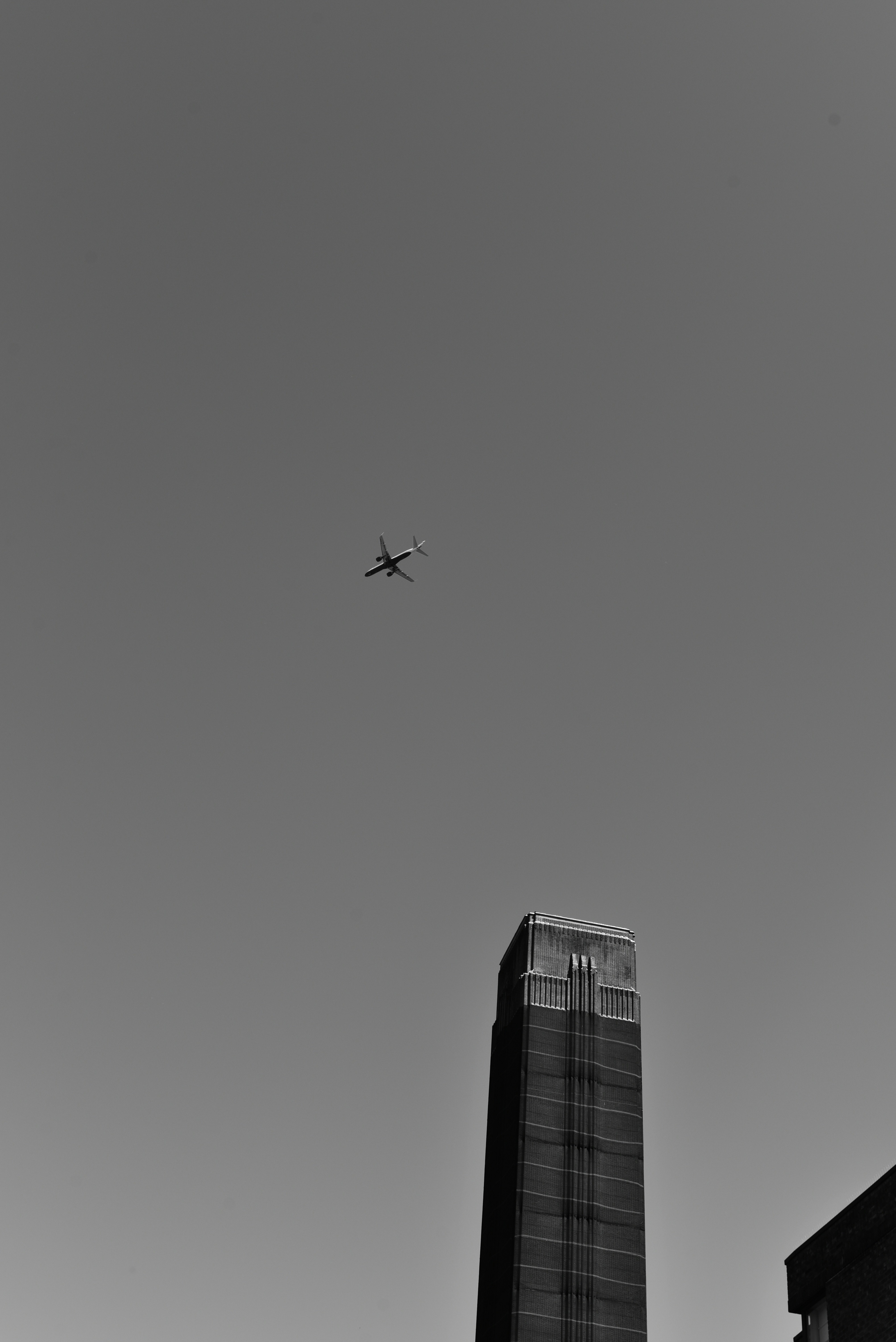 Jet over the skyline: a lone aircraft against a stark vertical tower