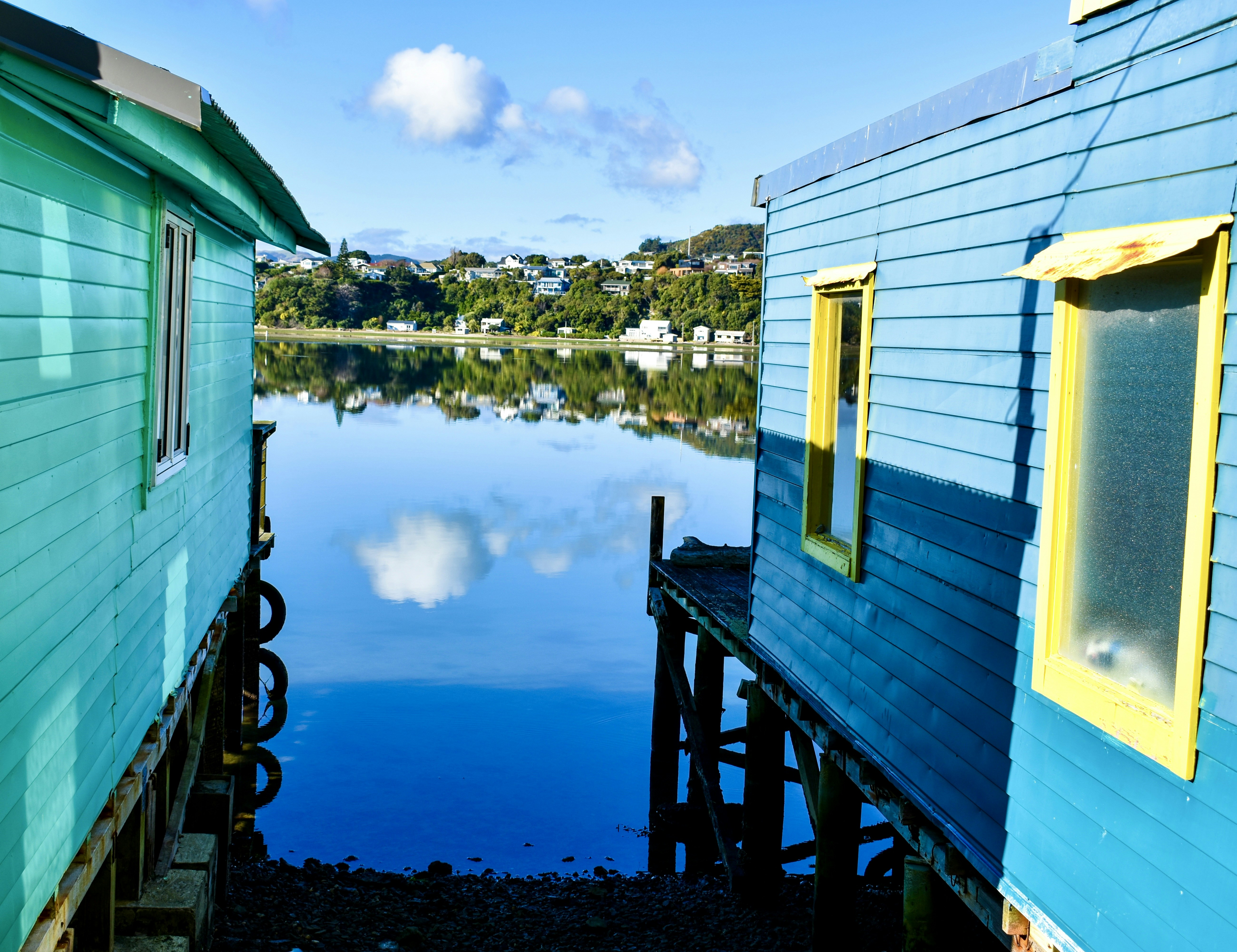 Colorful boathouse corridor framing a mirrored harbor
