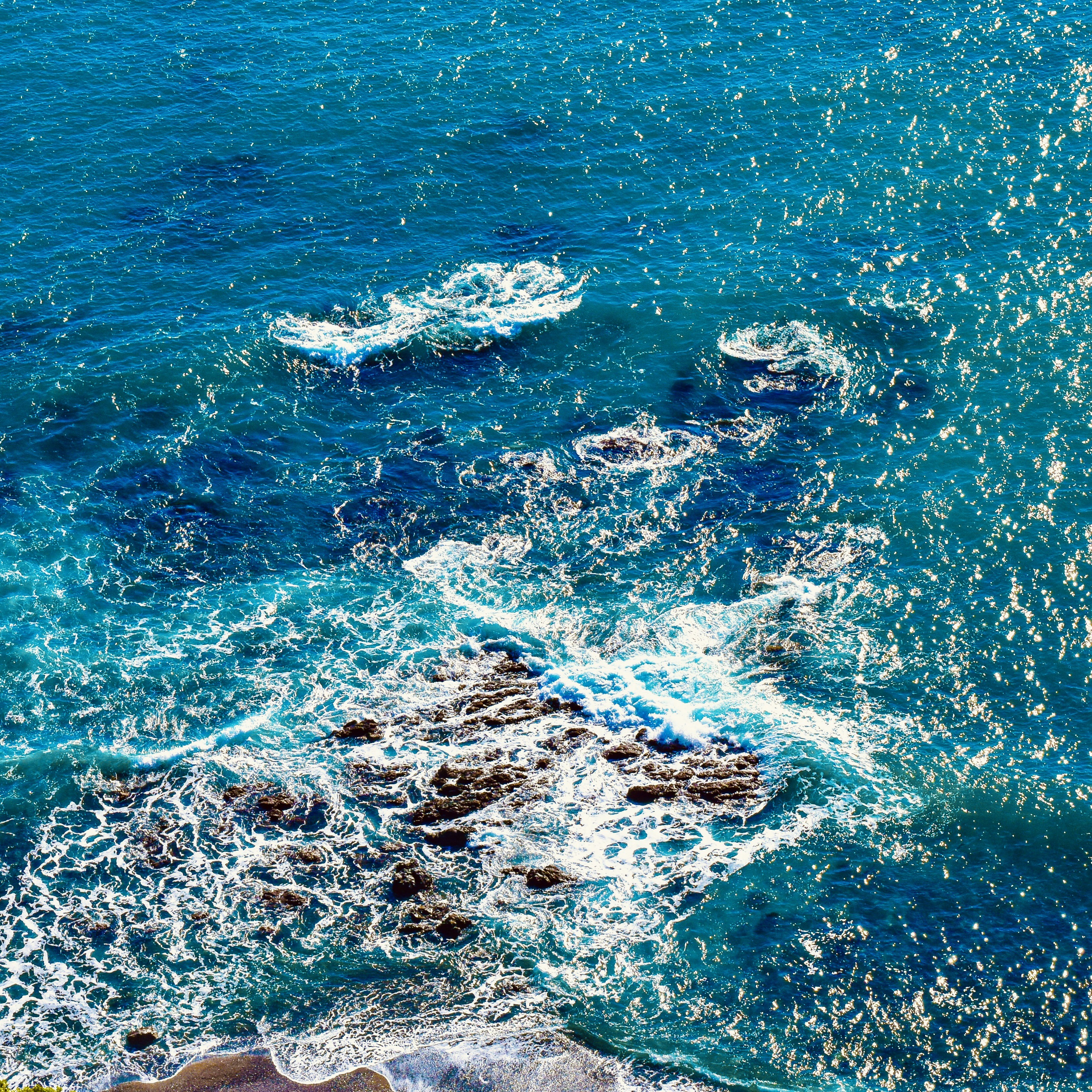 Azure Crest: Sunlit Swirls Over Bouldered Reef