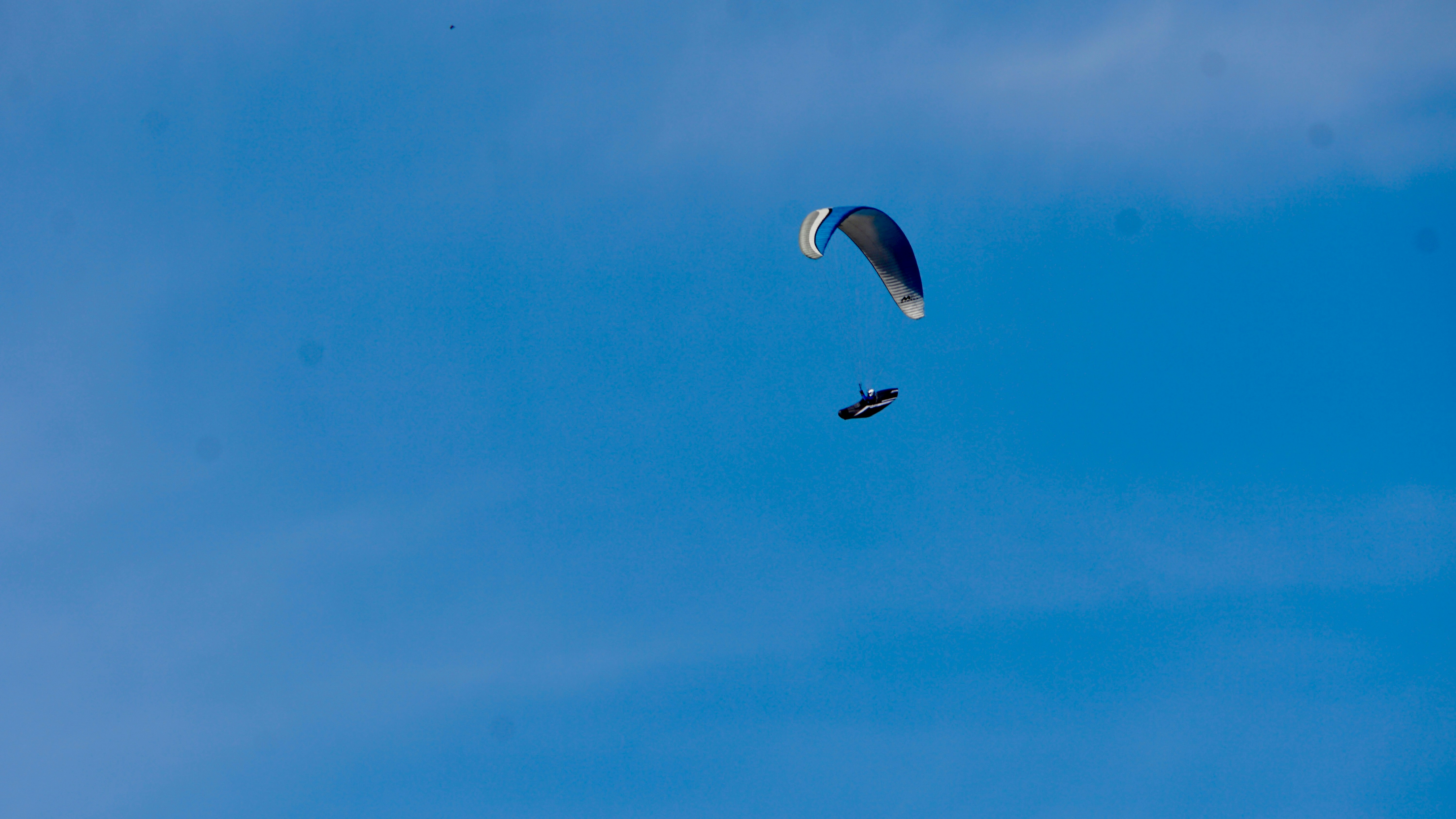 High Above Quiet Blue: A Solo Paraglider Cuts Across a Clear Sky