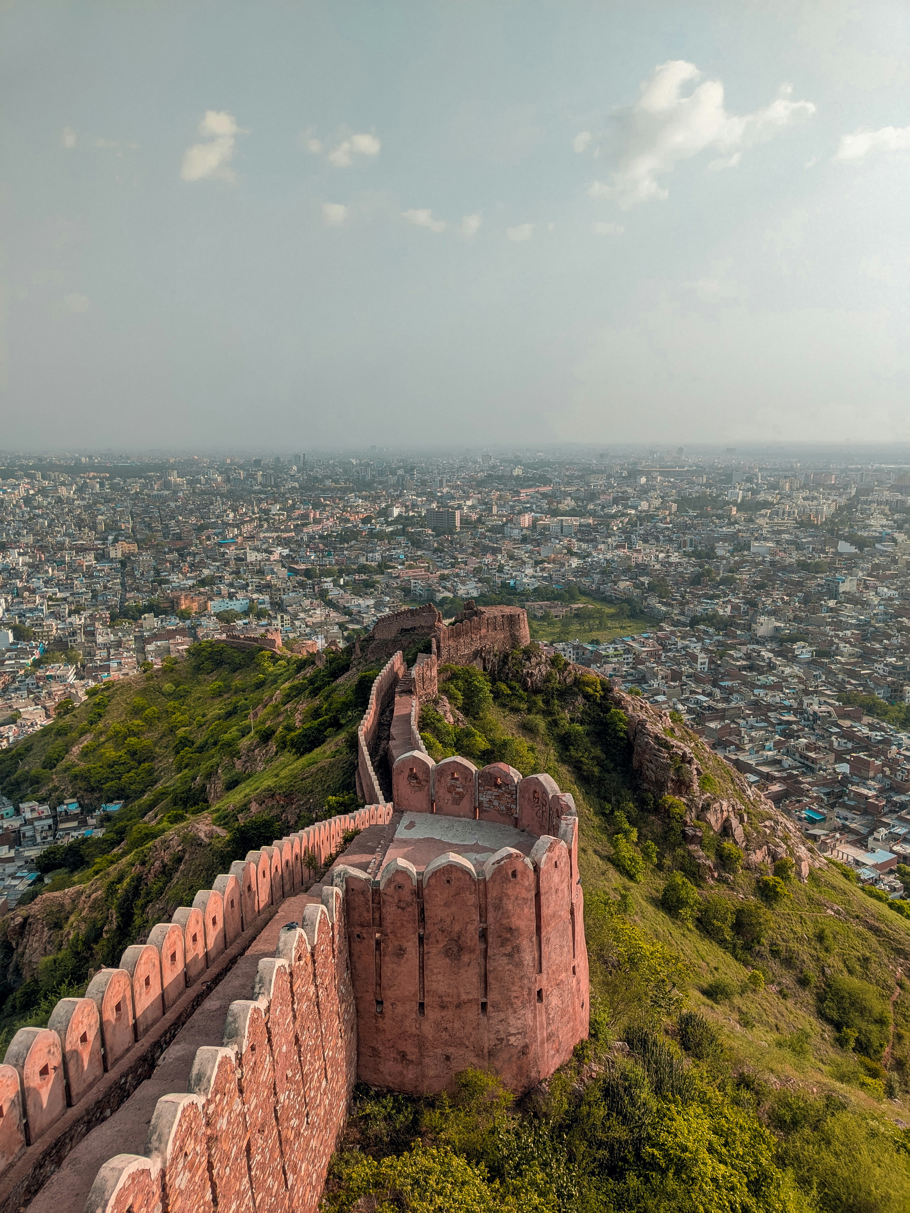 Winding fort wall on a hill overlooking a sprawling city.