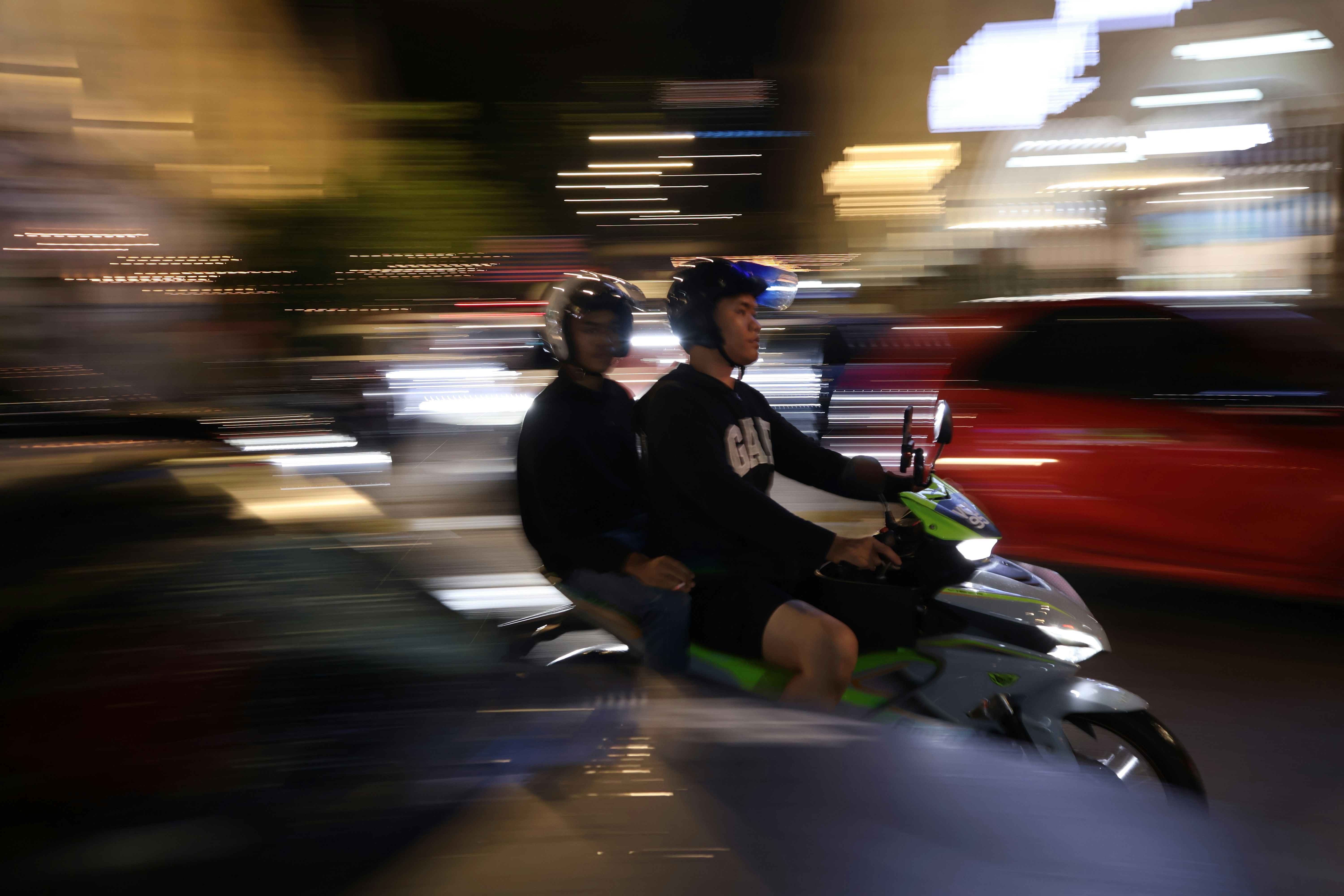 Night Ride Blur: Two Riders on a Neon-Streaked Scooter