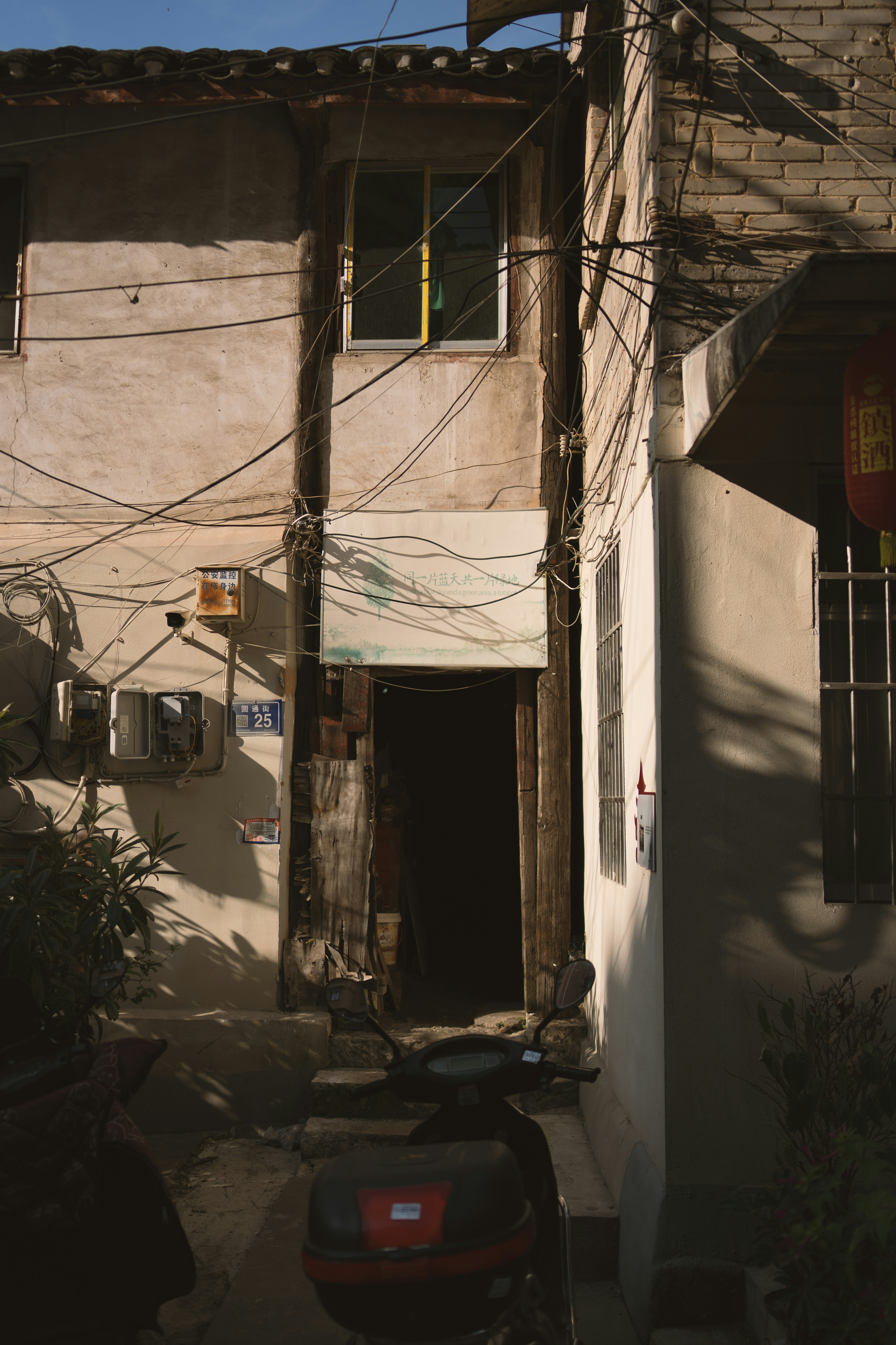 Doorway into the Narrow Alley: A Sunlit Entrance Framed by Wires and Shadows