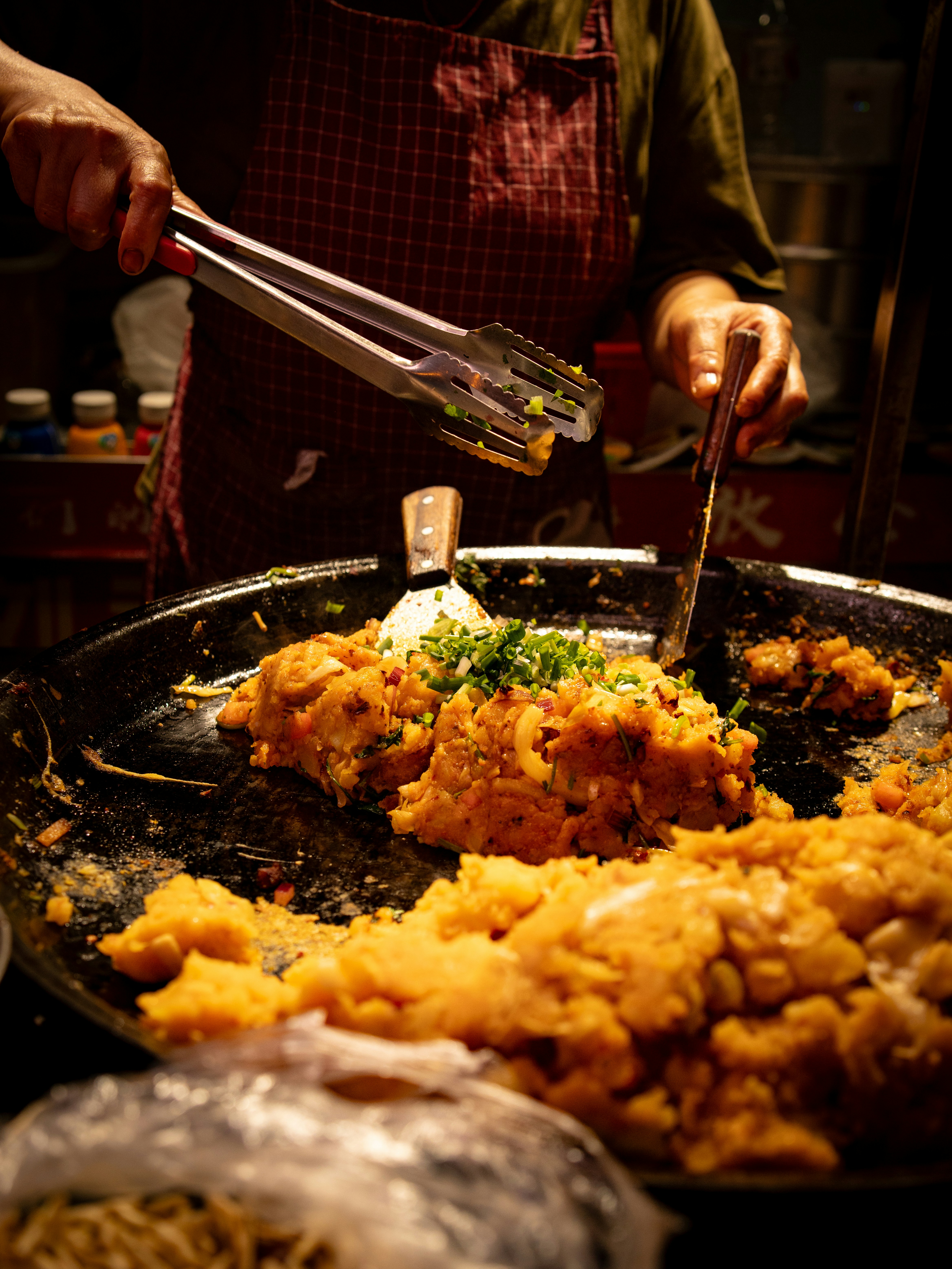 Flaming skillet: Hands shaping golden morsels under a chef’s steel tongs