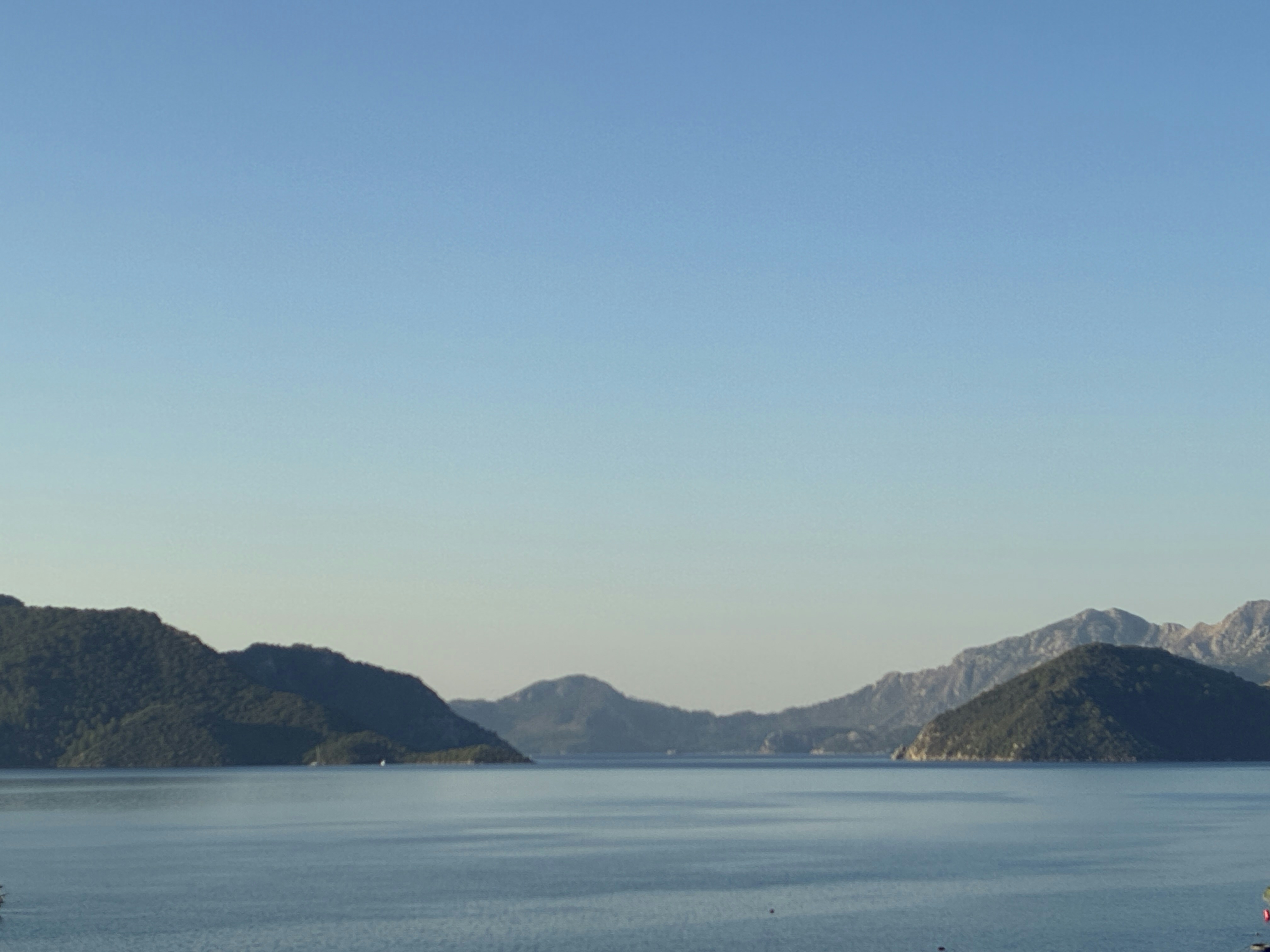 Serene alpine fjord with distant mountains and a glassy lake at blue-hour light. A clean horizon and soft gradients define the scene.