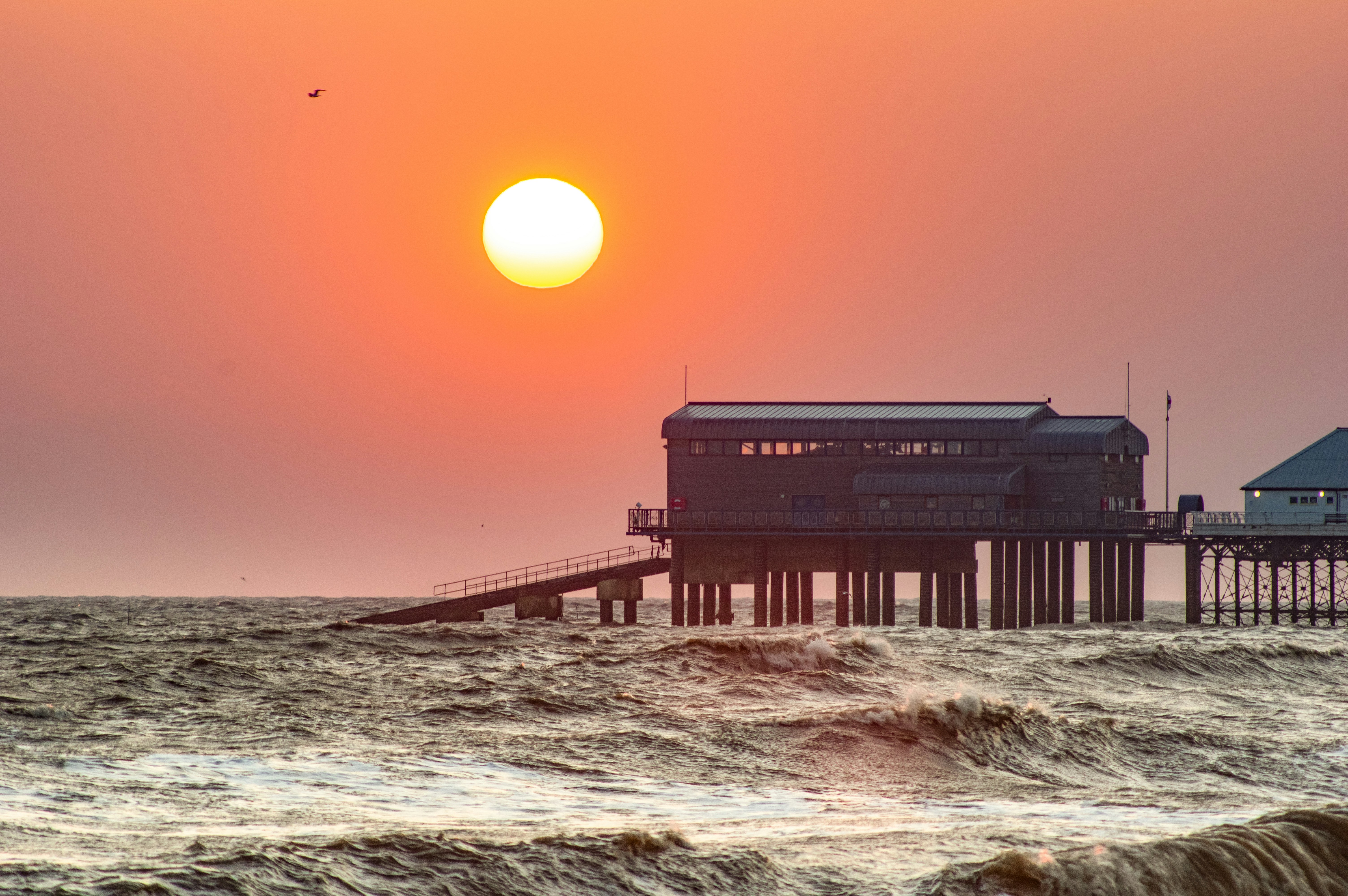 Sunlit Pier: A Quiet Horizon Over Rough Seas