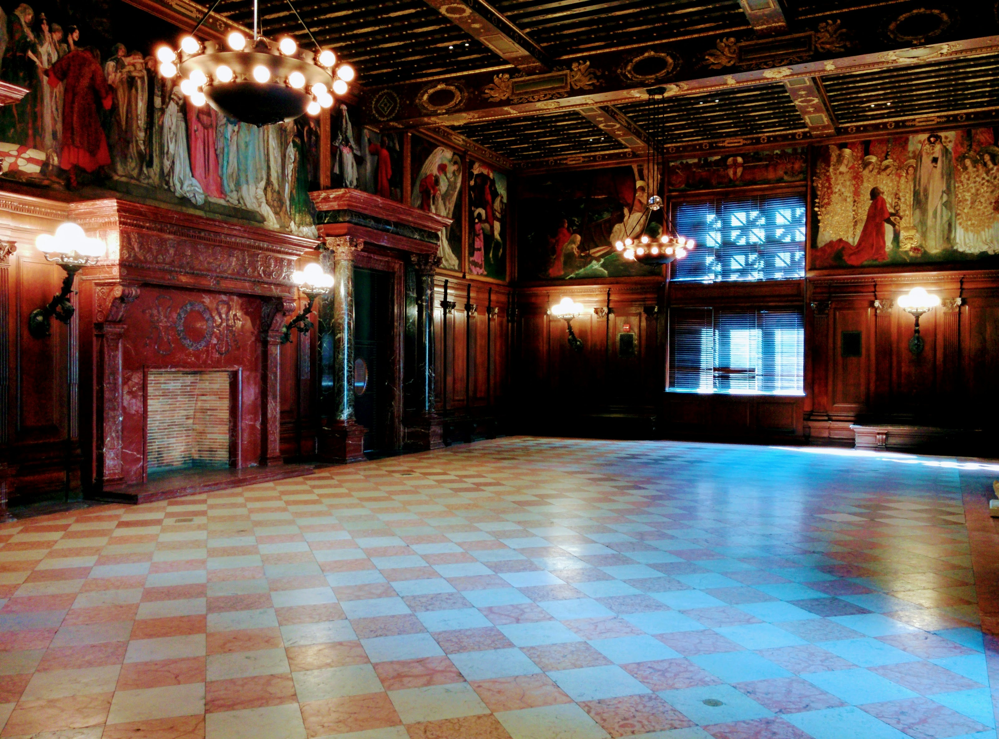 Dimly lit ballroom with checkerboard floor, gilded walls, and murals under an ornate ceiling; a quiet, historic space awaiting movement. (Note: Location appears to be a decorative interior, not a logo or illustration.)