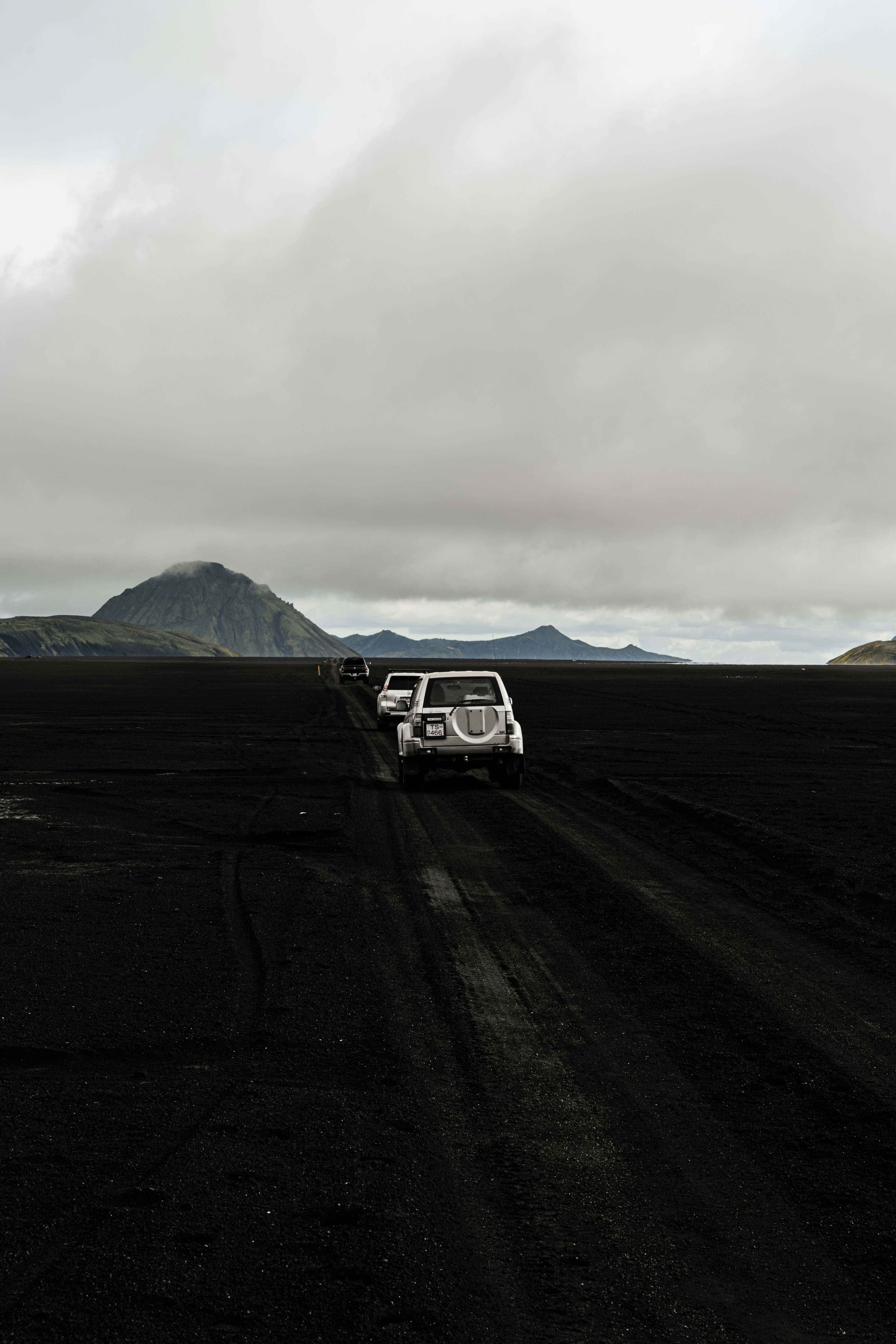 Midnight Tracks: A lone SUV Traverses an Expansive Black Beach