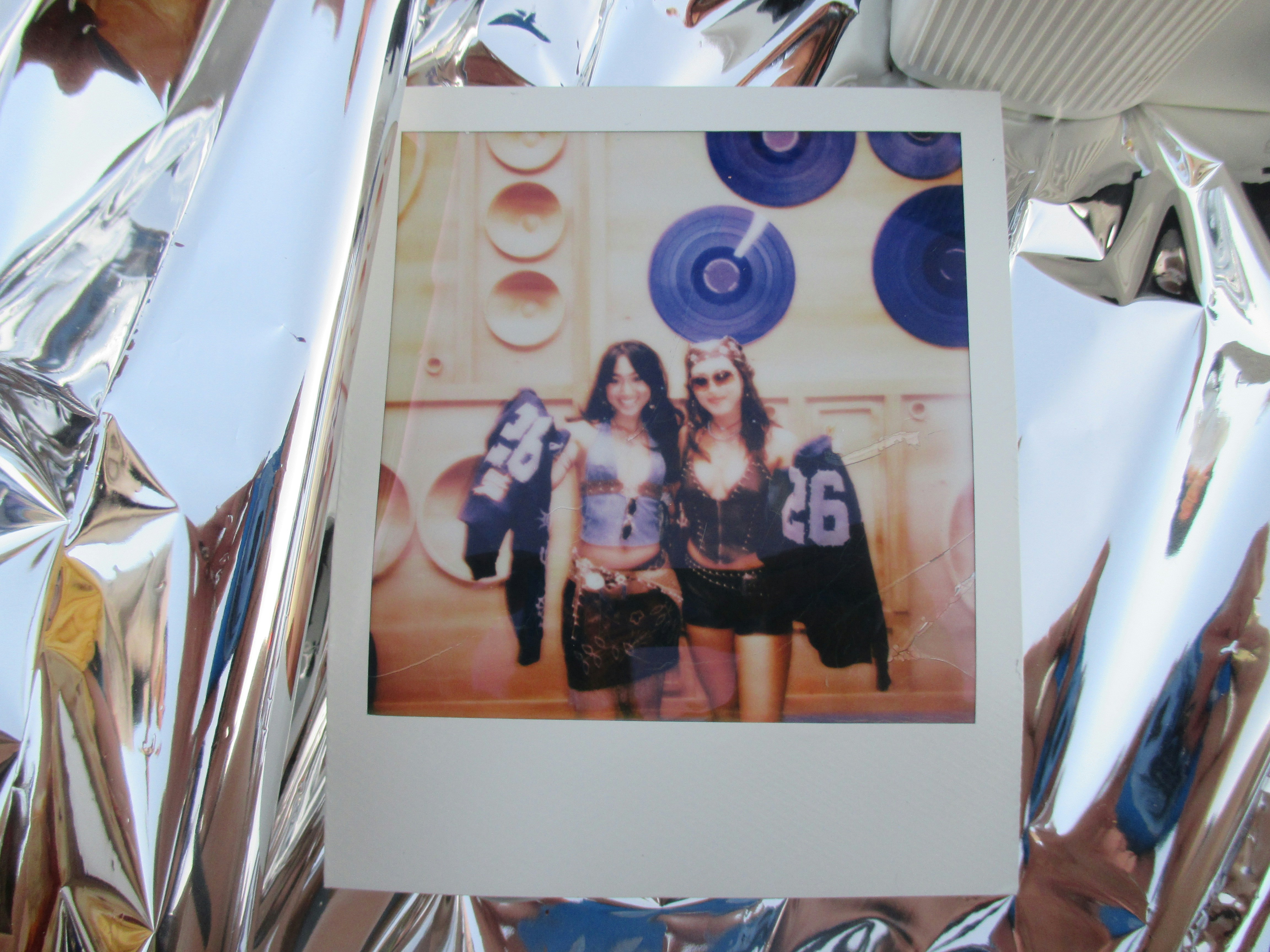Polaroid of two women holding jerseys on silver foil