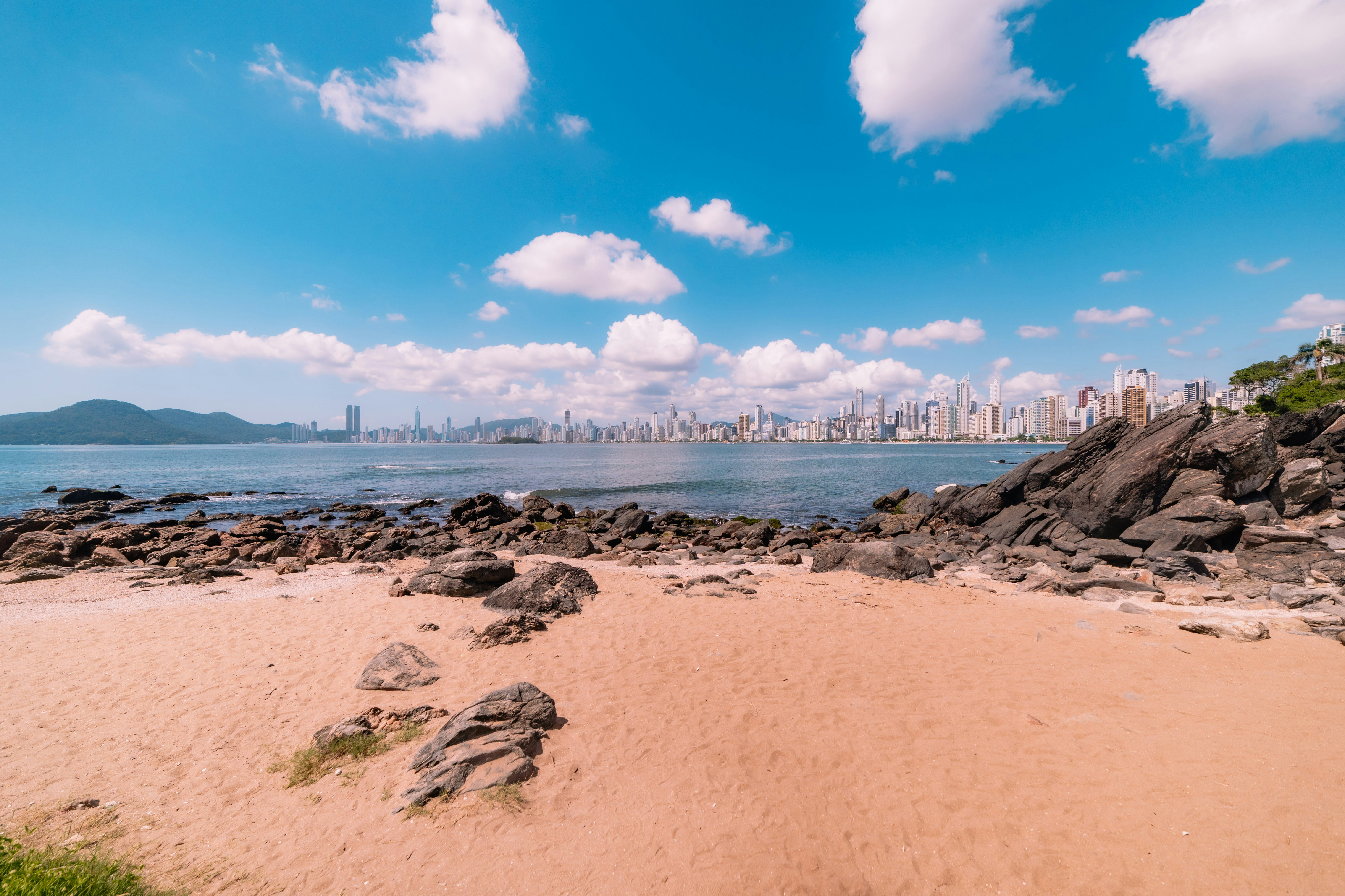 Coastal Skyline with Sand and Rocks Framing a Distant City
