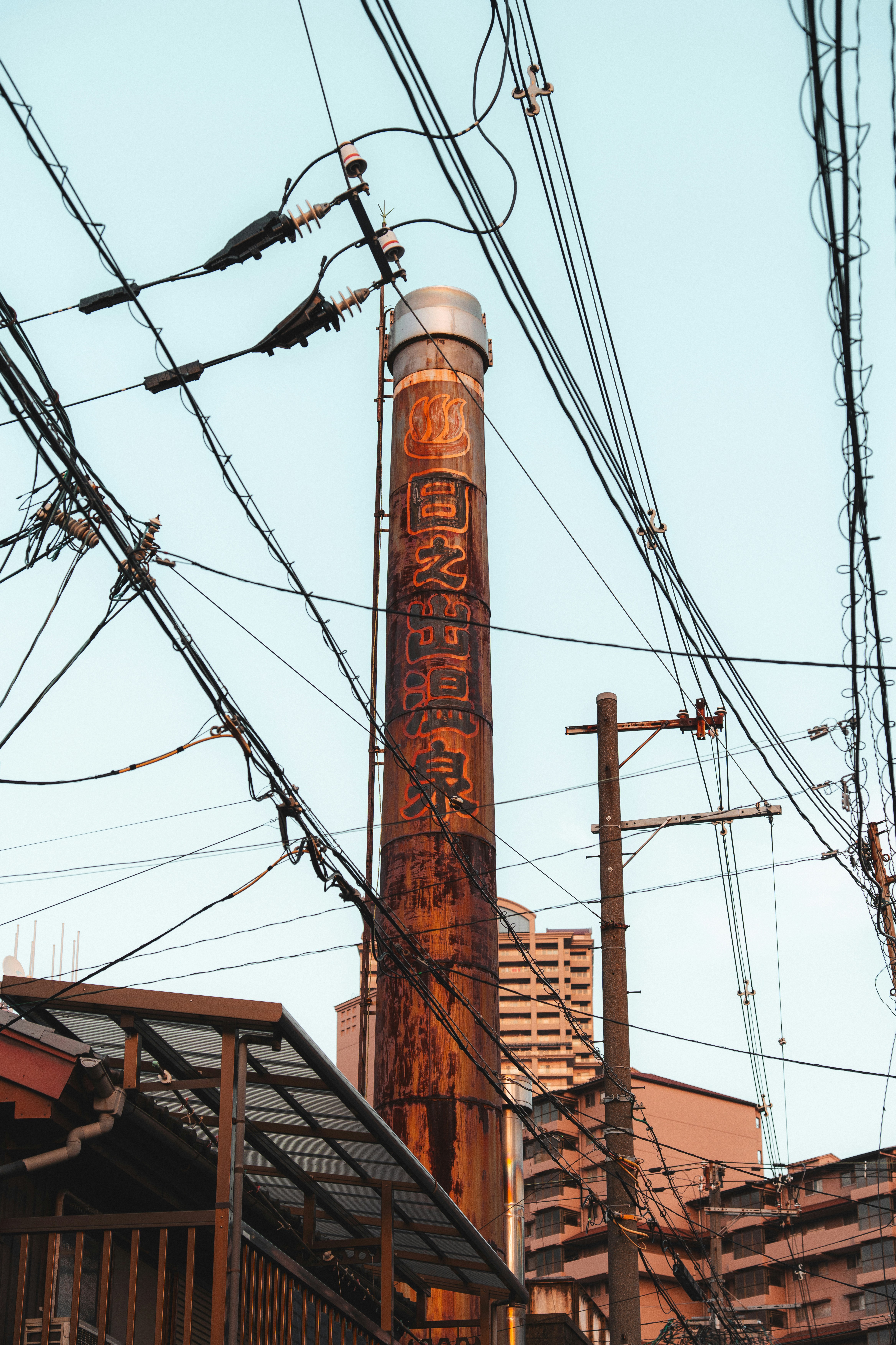 Electric Signal: A Weathered Neon Pillar Among Tangled Wires