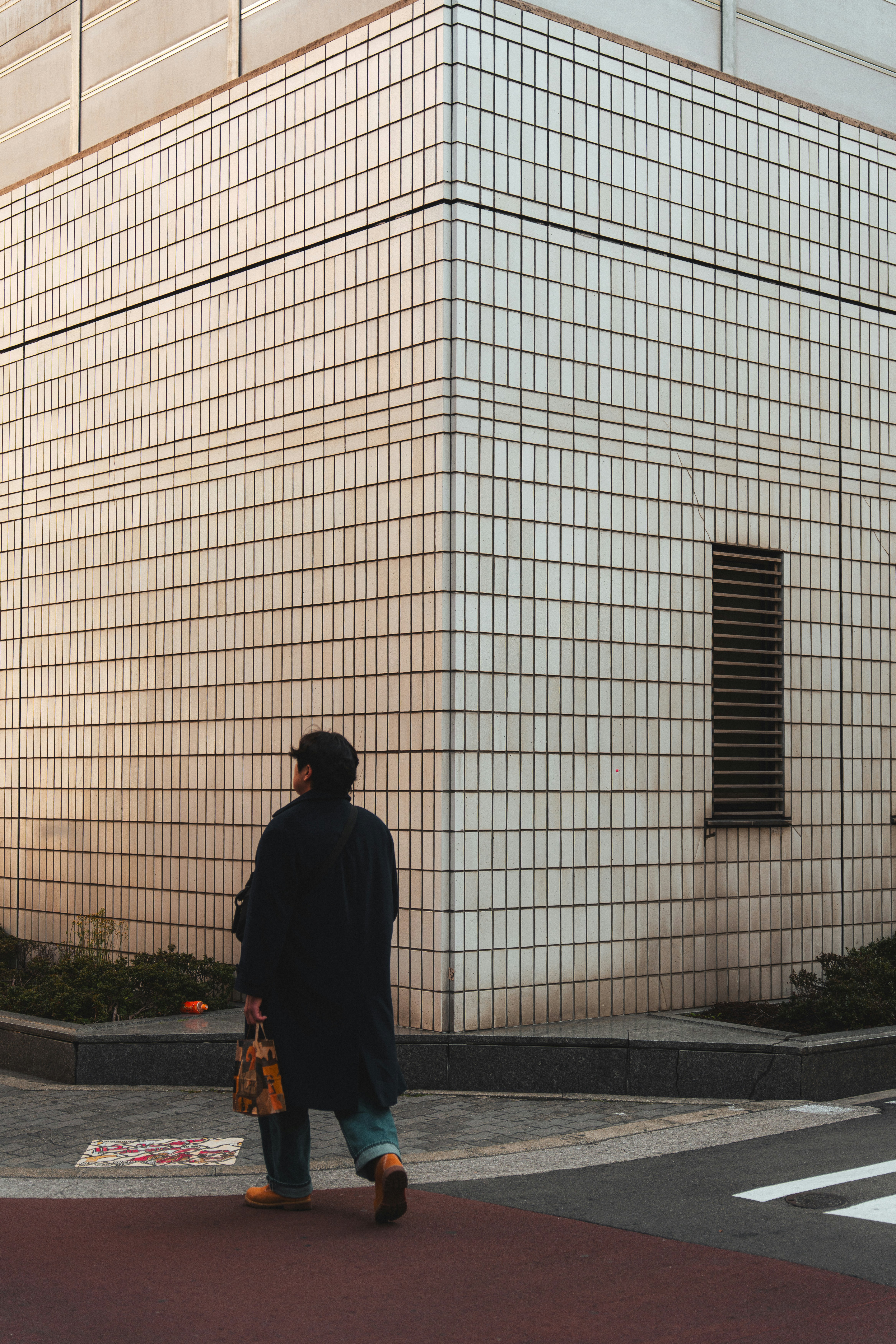 Urban solitude: a passerby near a tiled wall