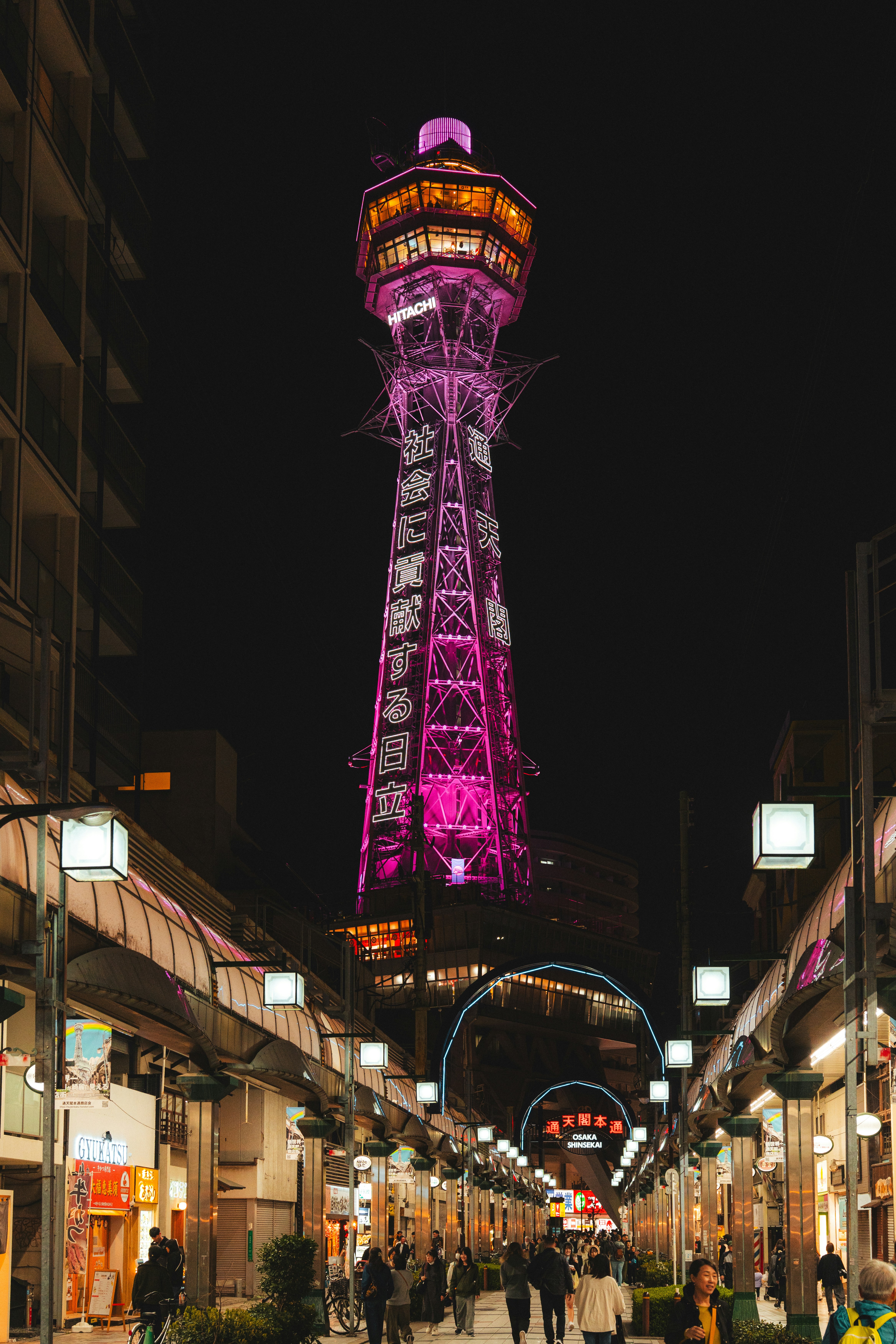 Neon Tower at Night: A Pedestrian Arc Beneath the Illuminated Spire