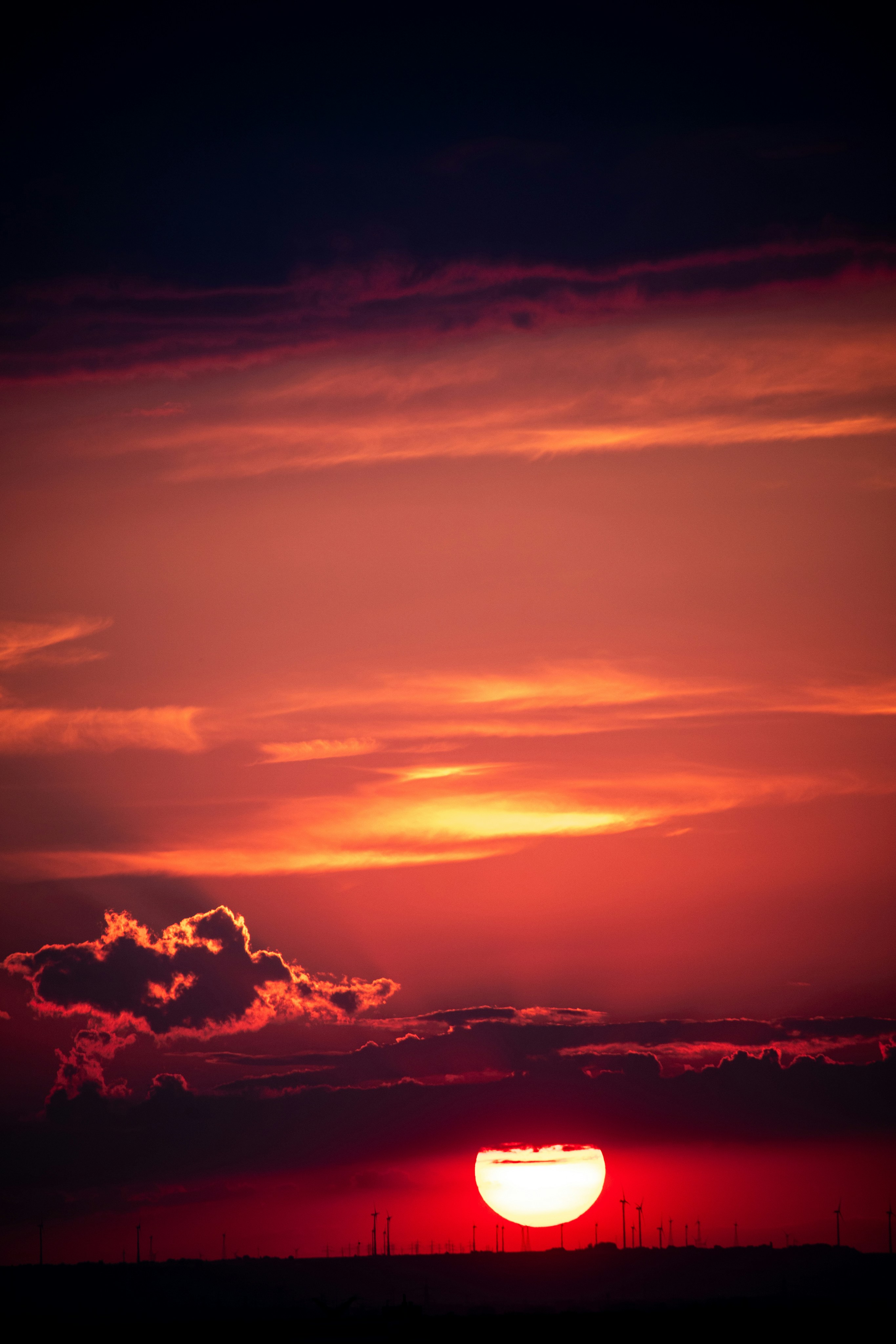 Red Sphere at Dusk: The Sun Sinks Below a Velvet Horizon