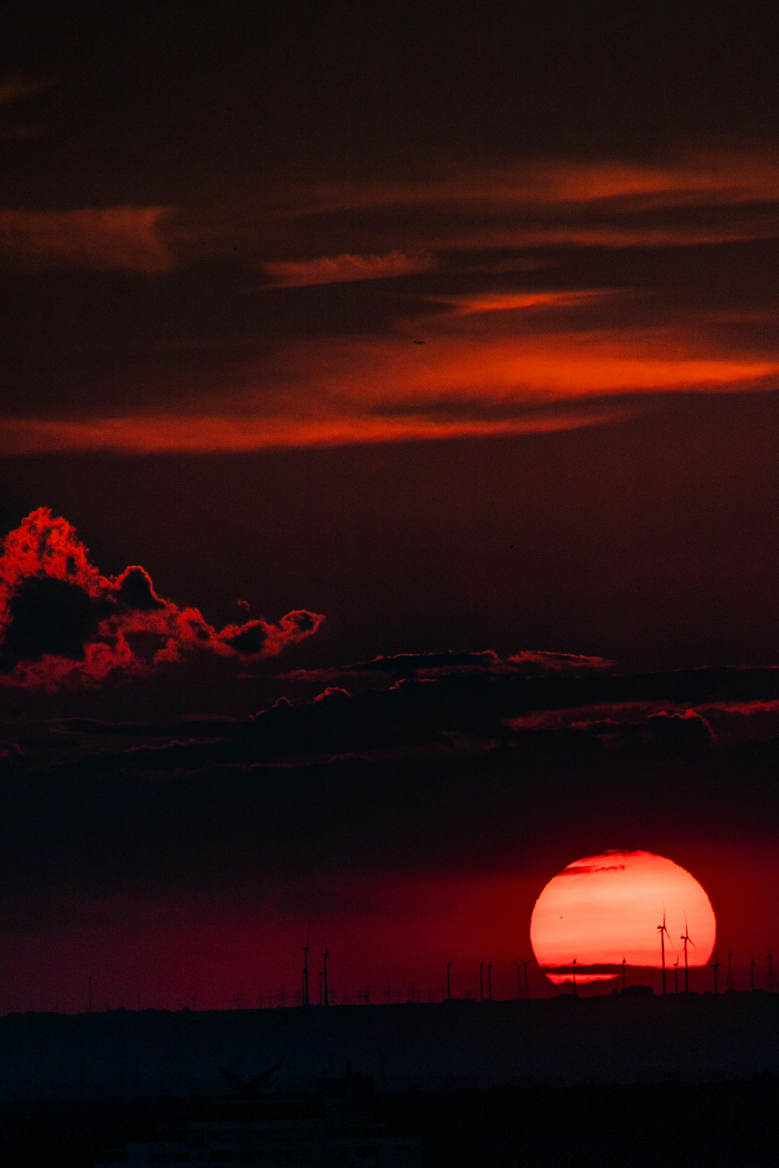 Crimson Horizon: The Sun Settles Behind a Silhouette of Distant Towers